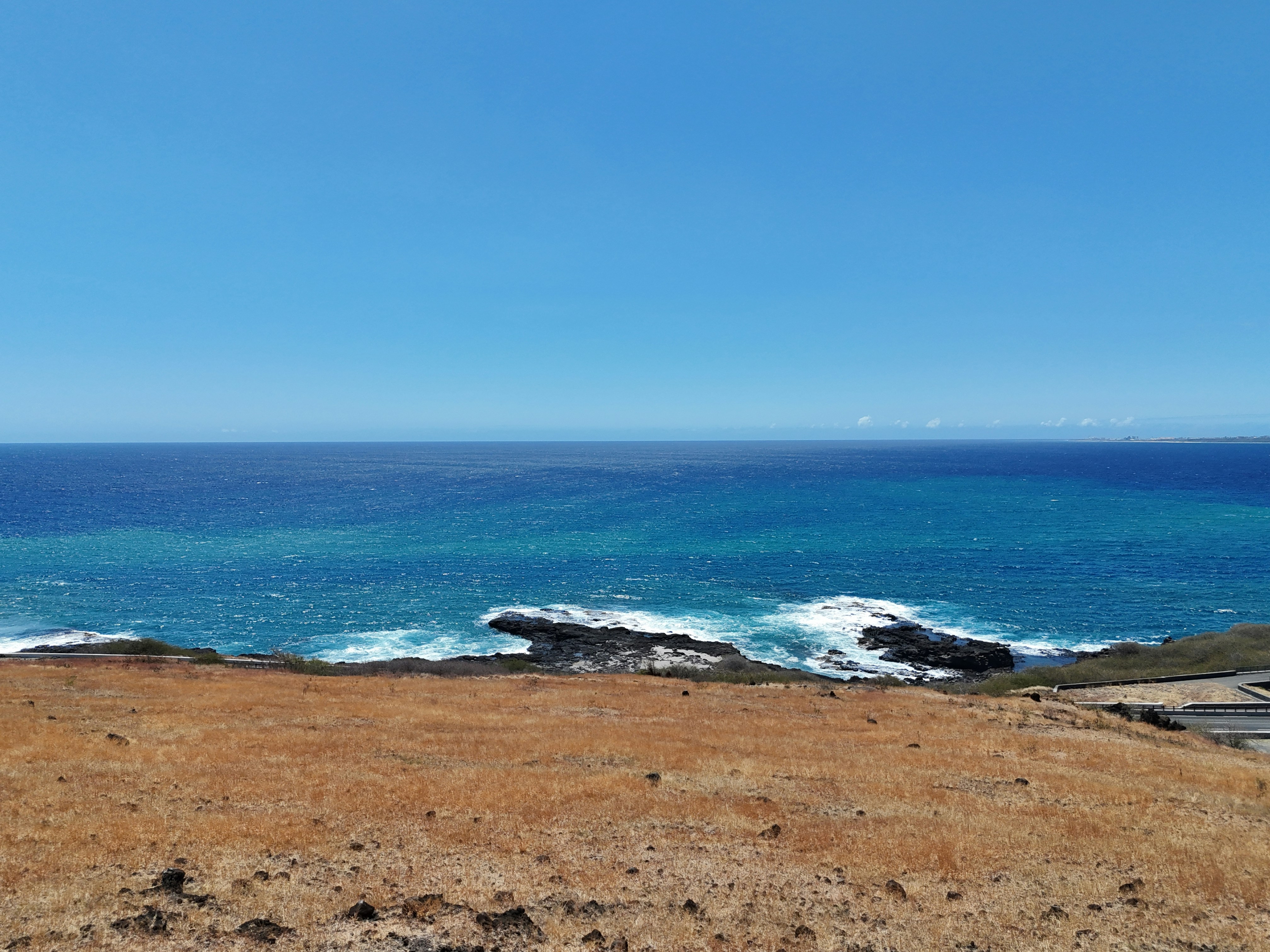 Waves crash on rocky shore under a clear blue sky