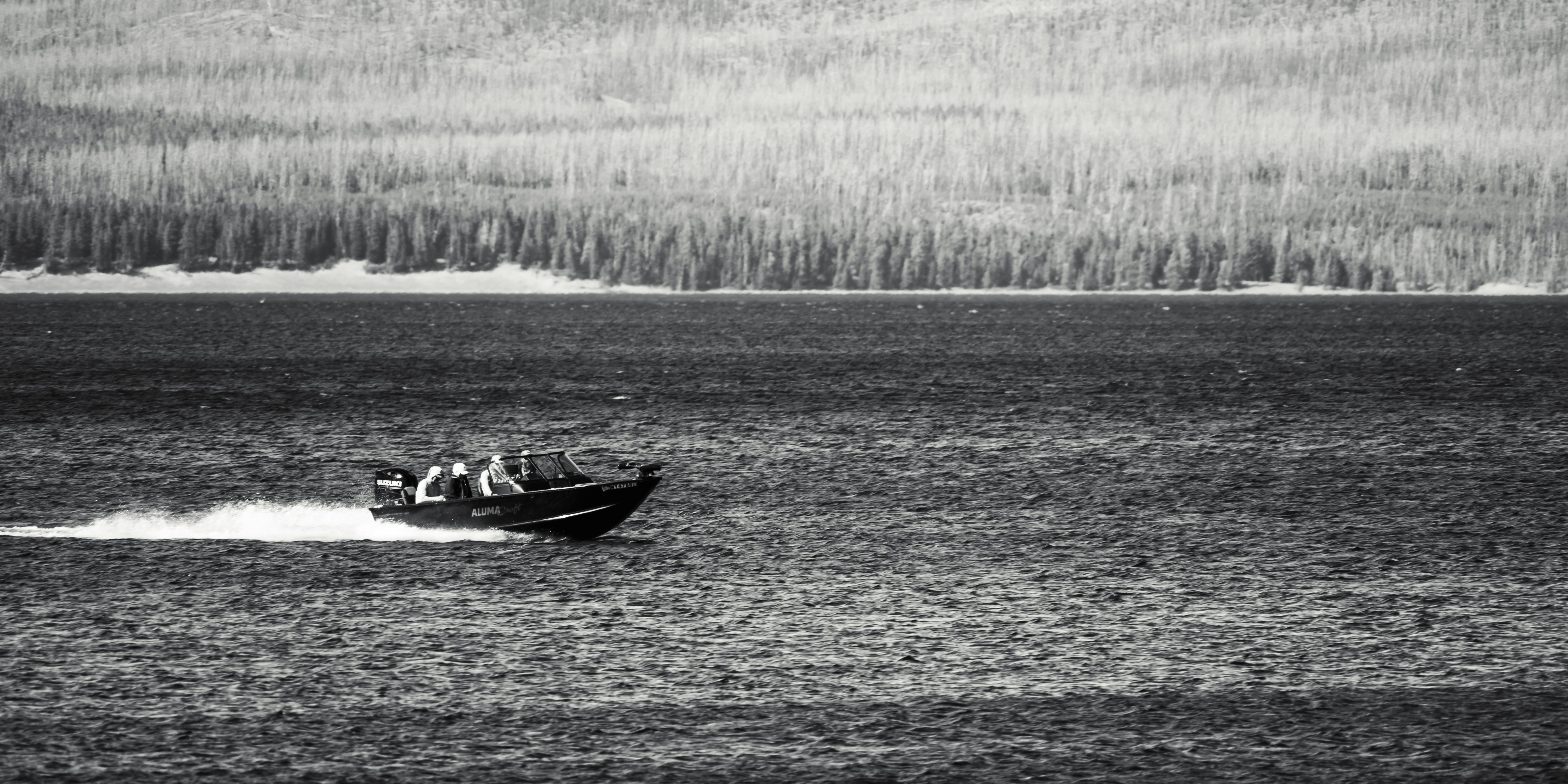 Boat with people speeding across a lake