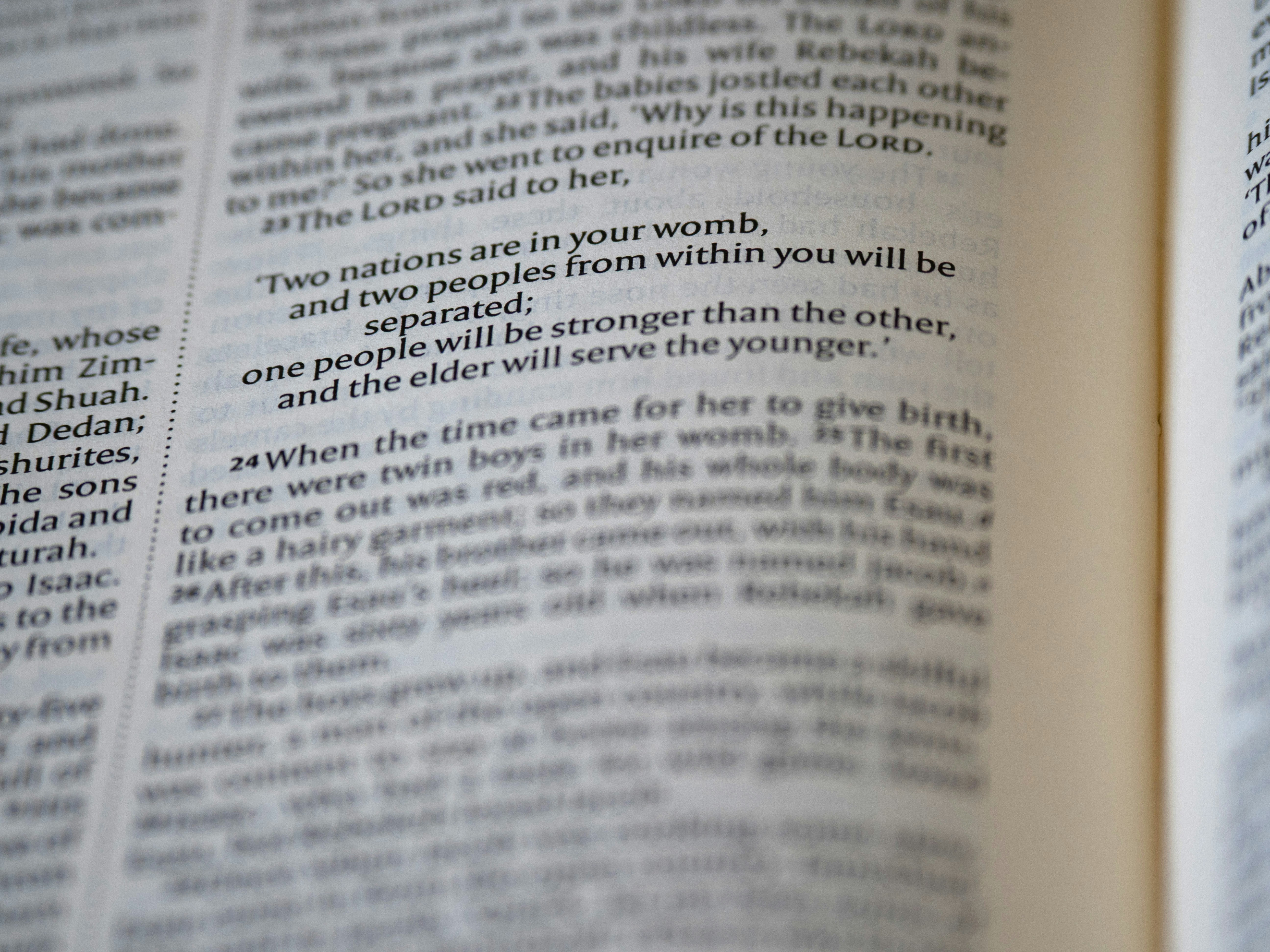 Close-up of an open Bible page featuring a passage about twins and their destinies. The text highlights themes of separation and strength.