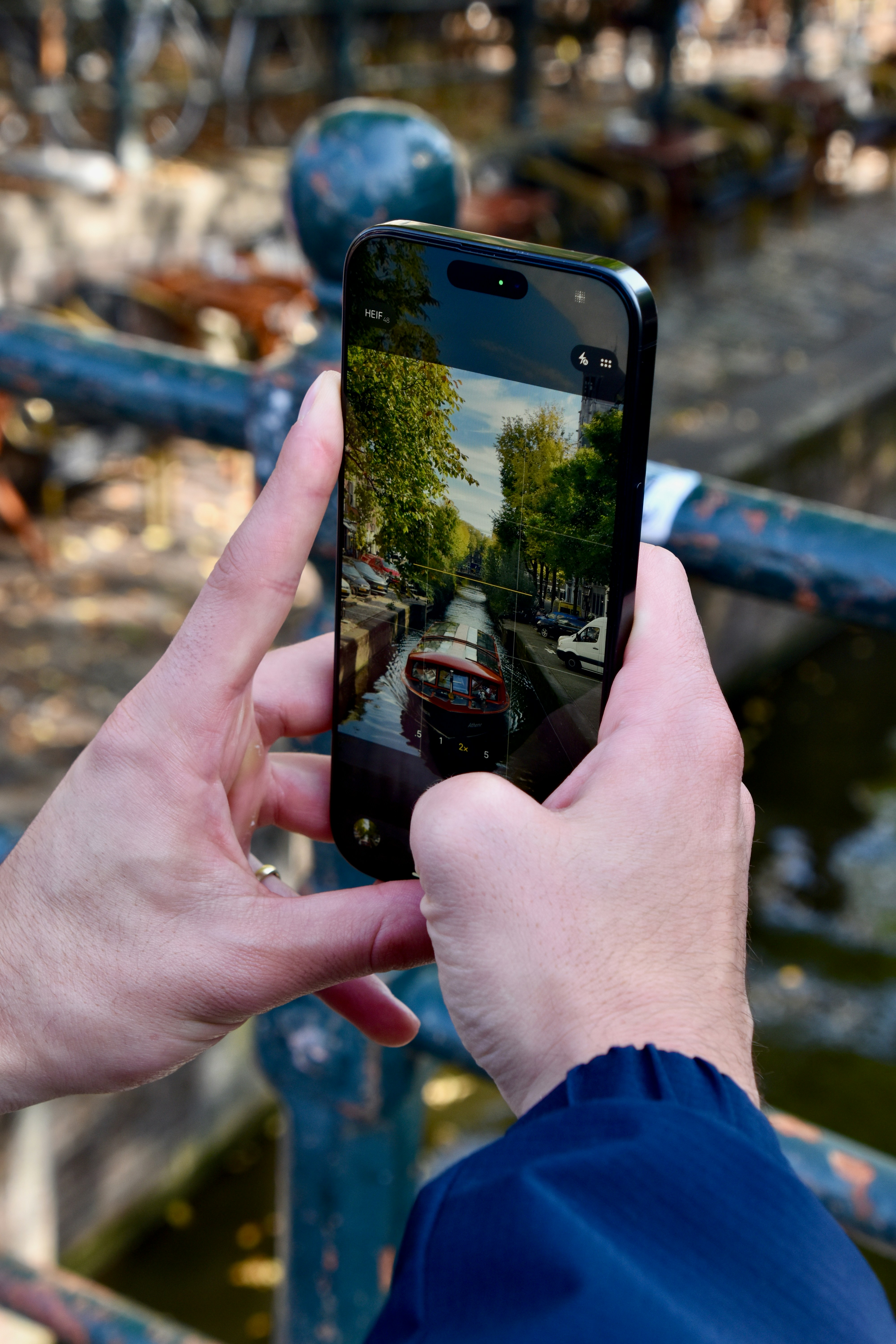Hands holding phone capturing canal scene