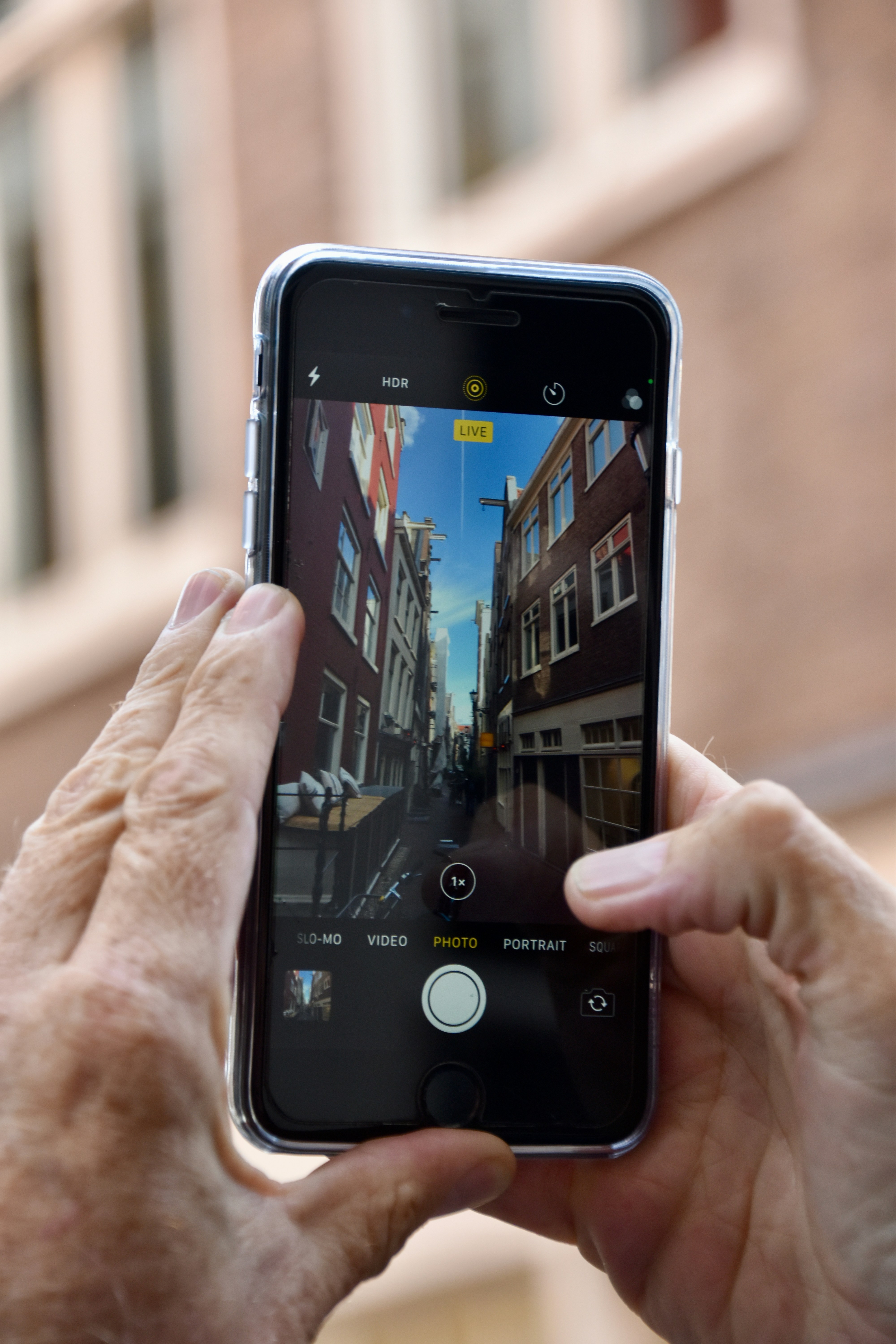 Hands holding phone, capturing narrow street buildings