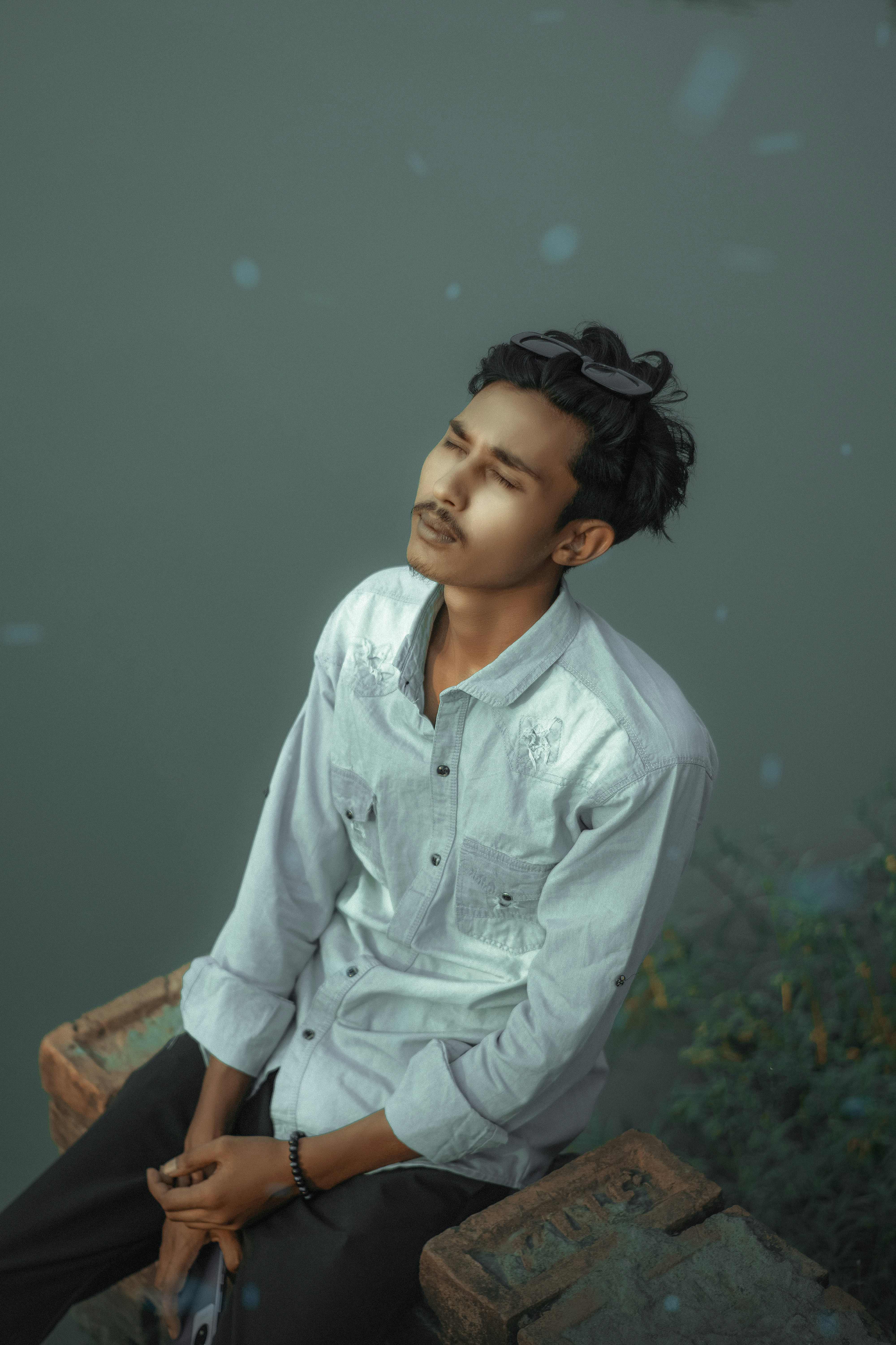 Man in white shirt sitting by the water