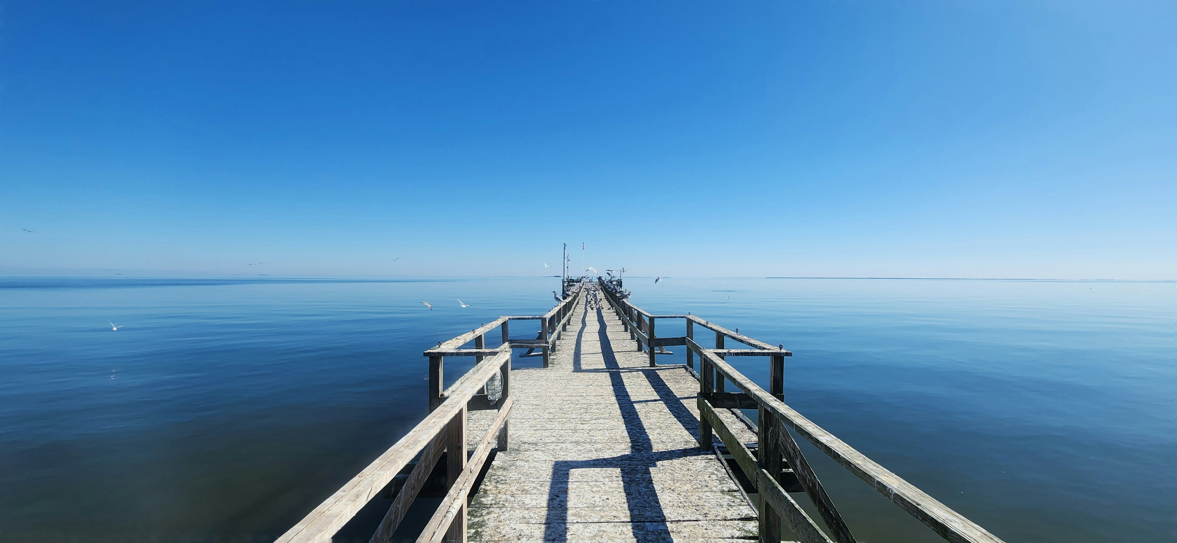 Chasapeak Bay Clavert County, MD, Meagan's Pier, October 2025. | Wooden pier extending into a calm, clear blue ocean.