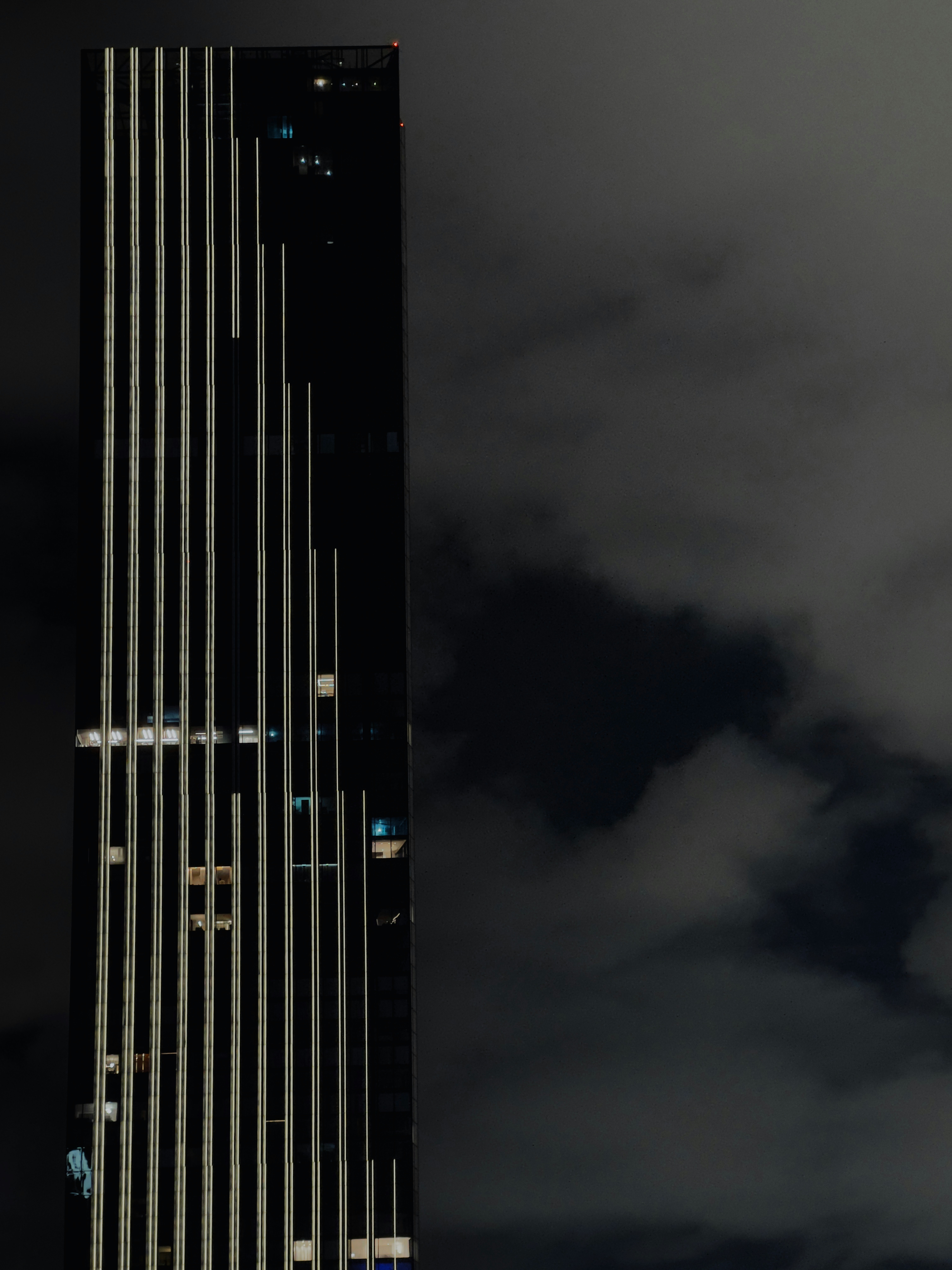 Modern skyscraper against a dark, cloudy sky