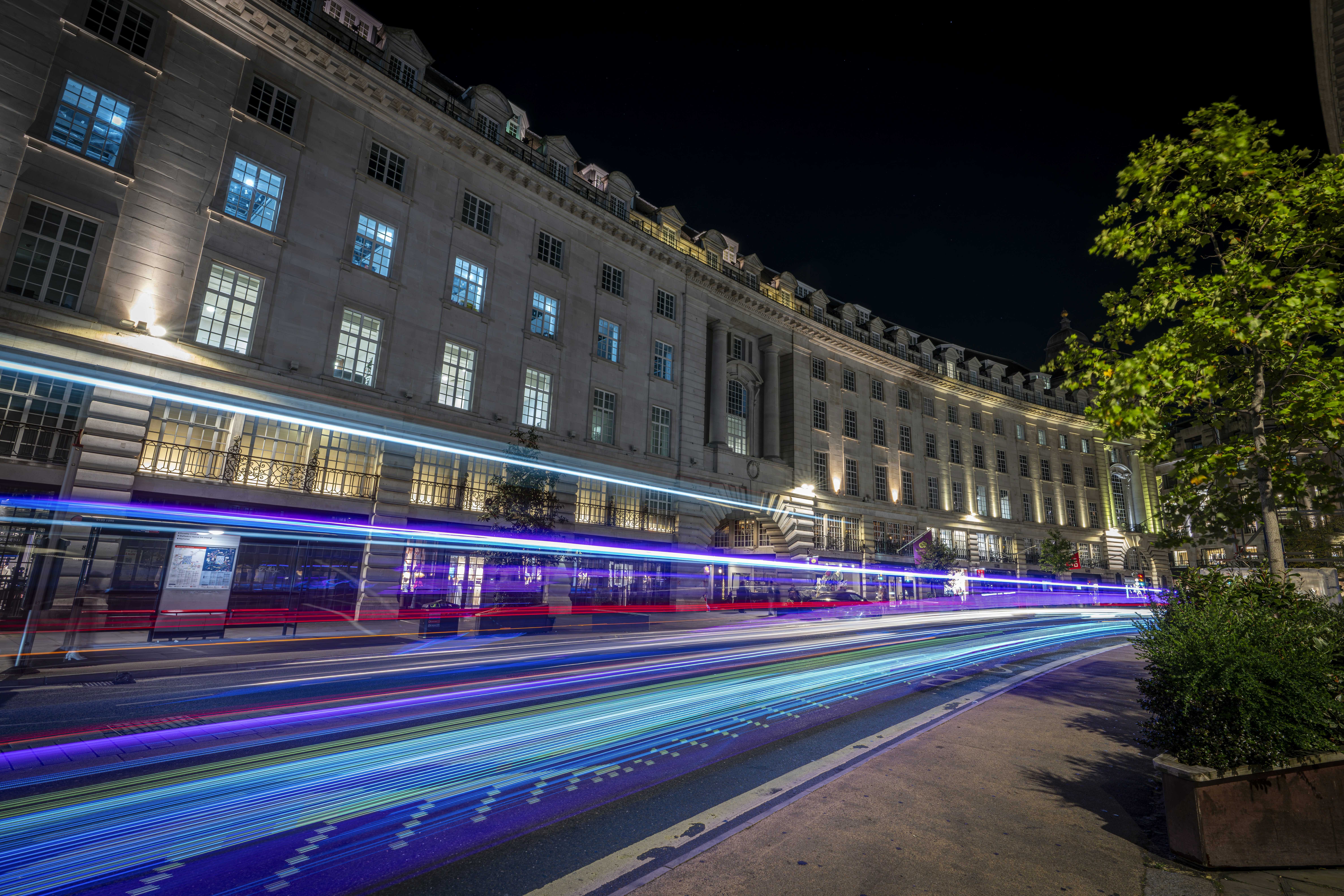 Light trails from vehicles on a city street at night.