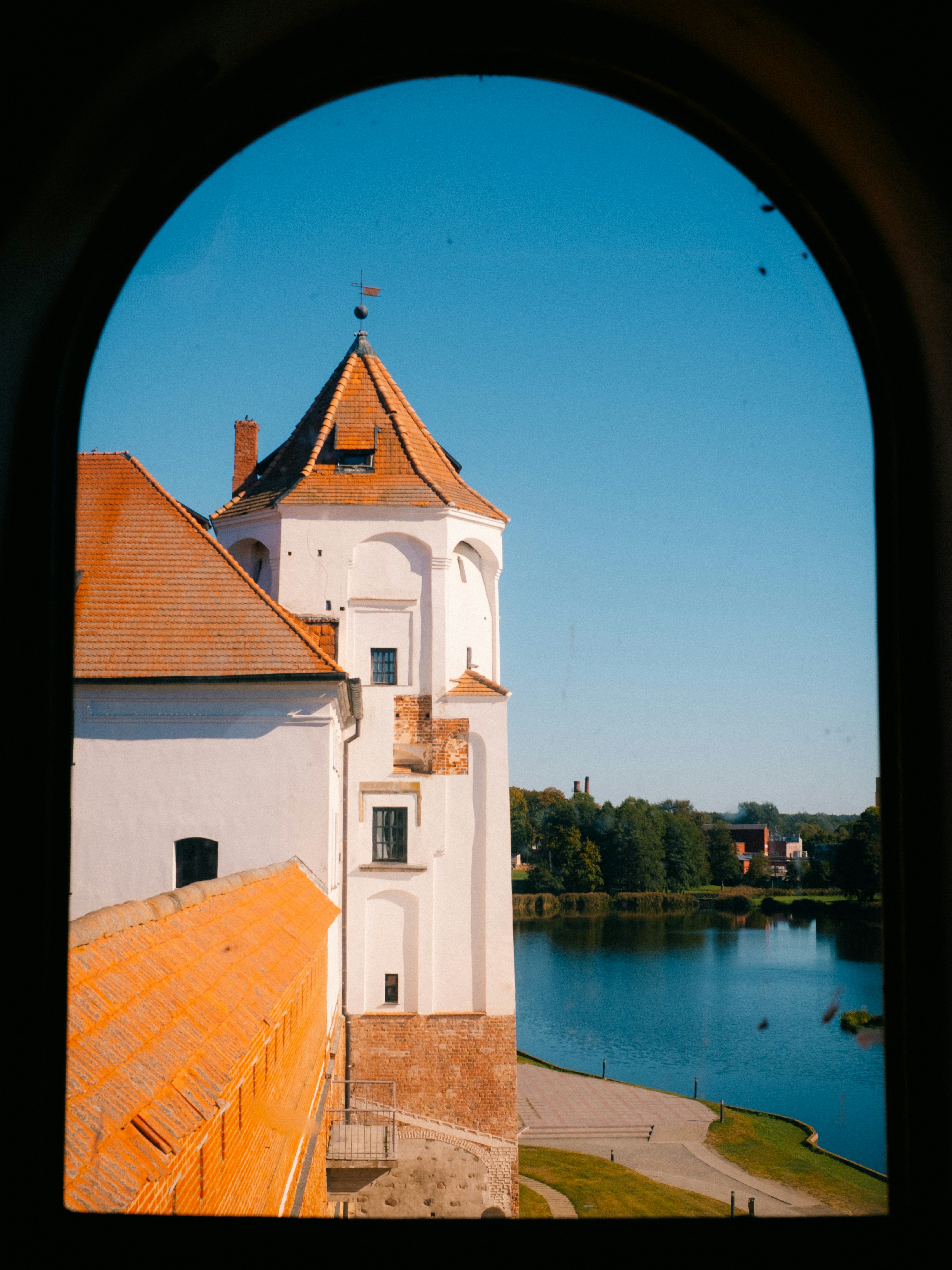 Castle | Castle tower overlooking a calm lake under blue sky