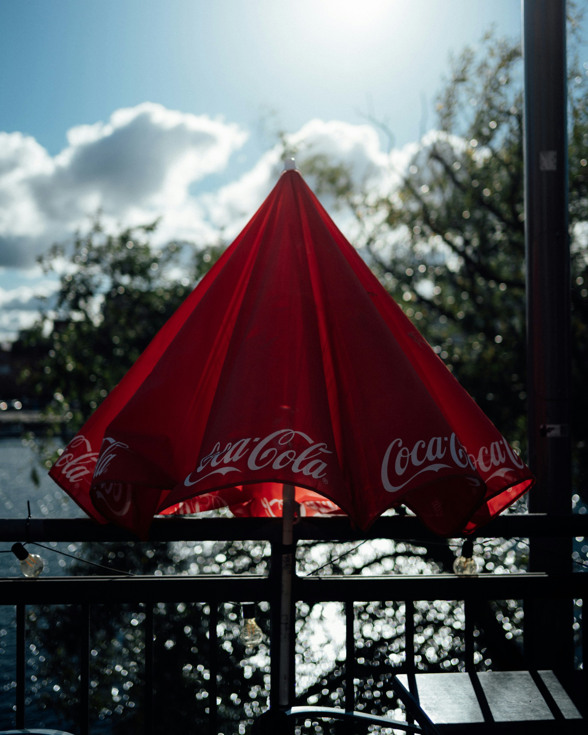 Red coca-cola umbrella against a cloudy sky