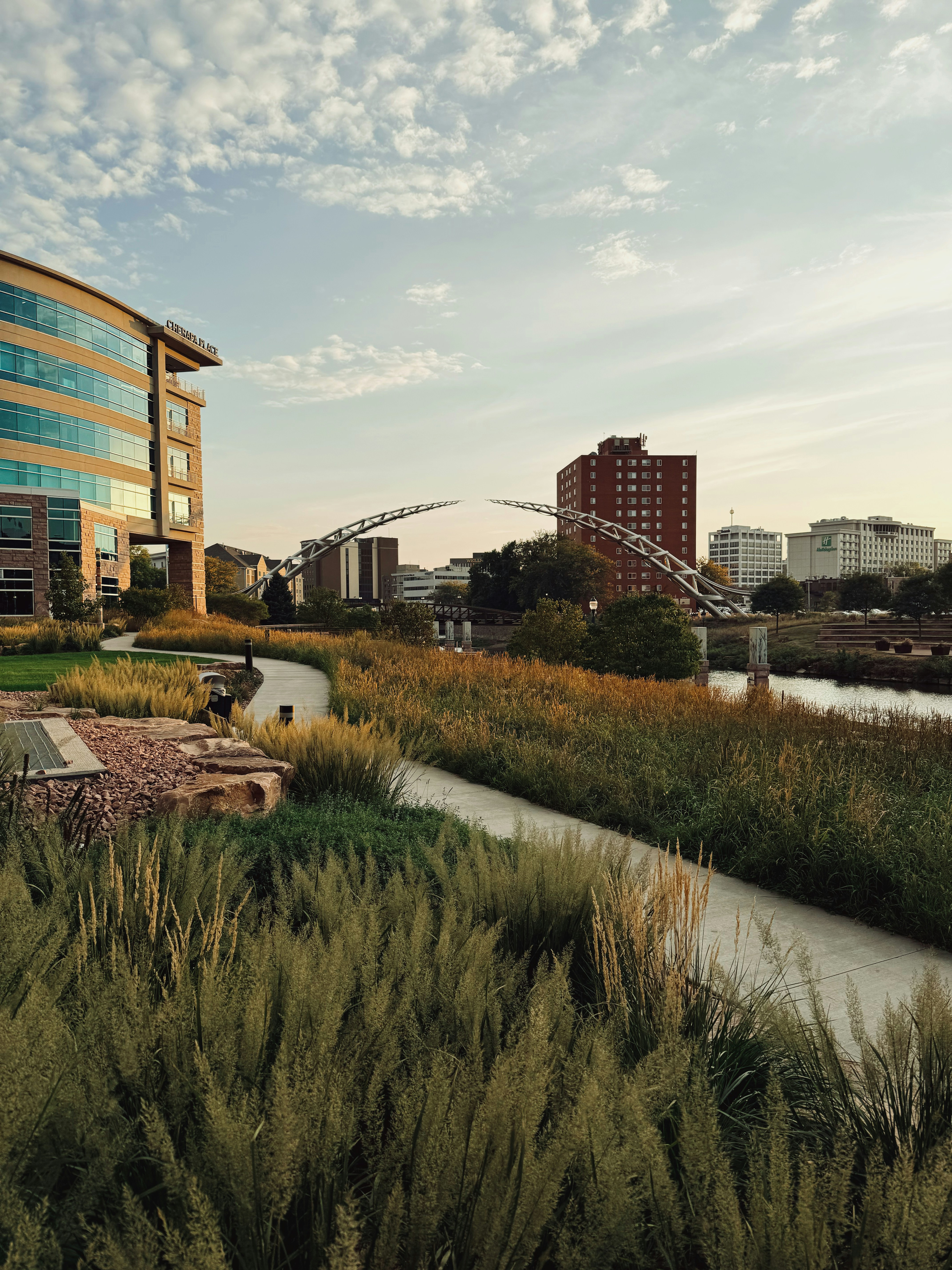Downtown Sioux Falls | Curving path through grassy area towards a modern bridge.