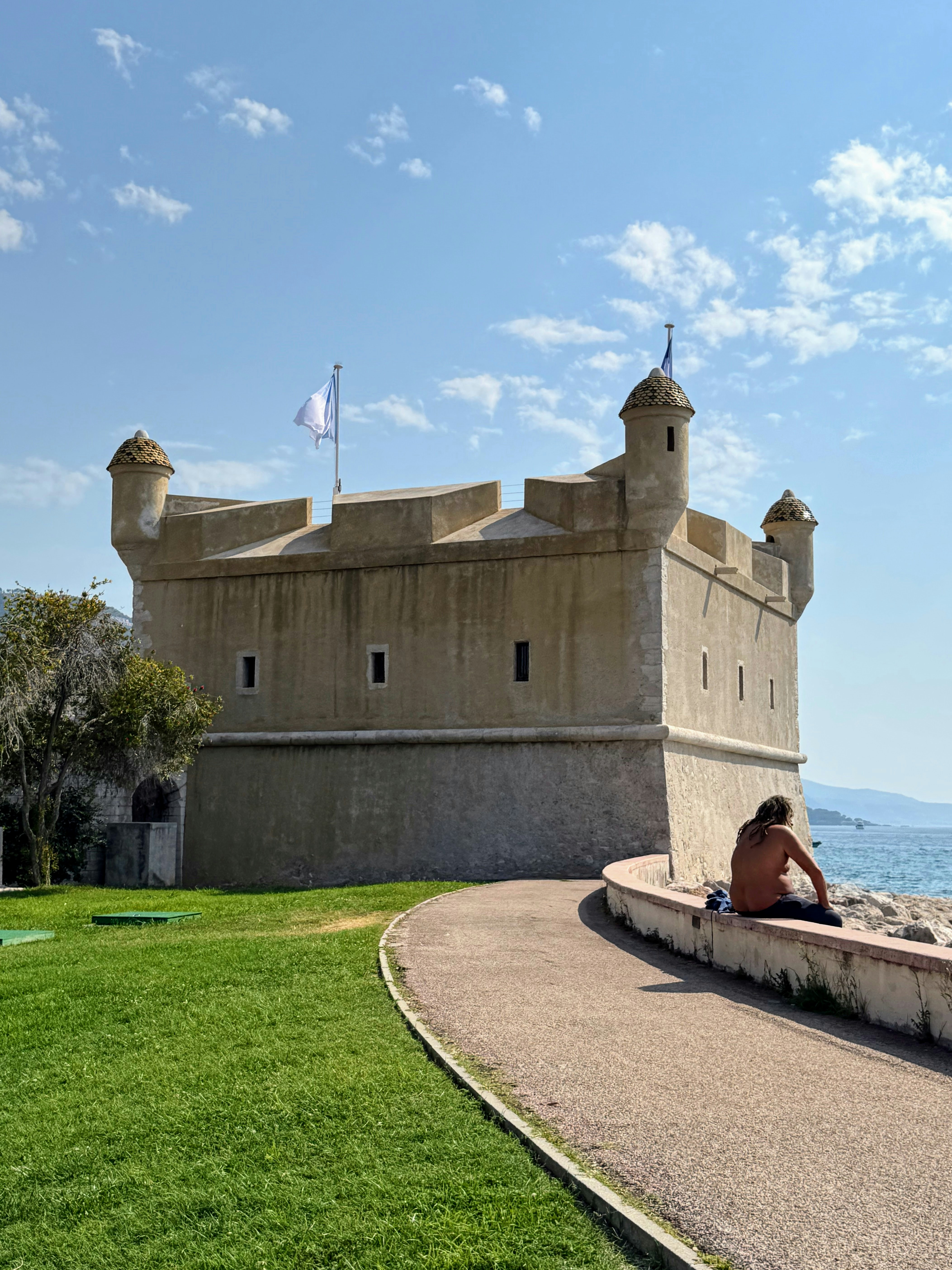 Fortress by the sea with a person sitting.
