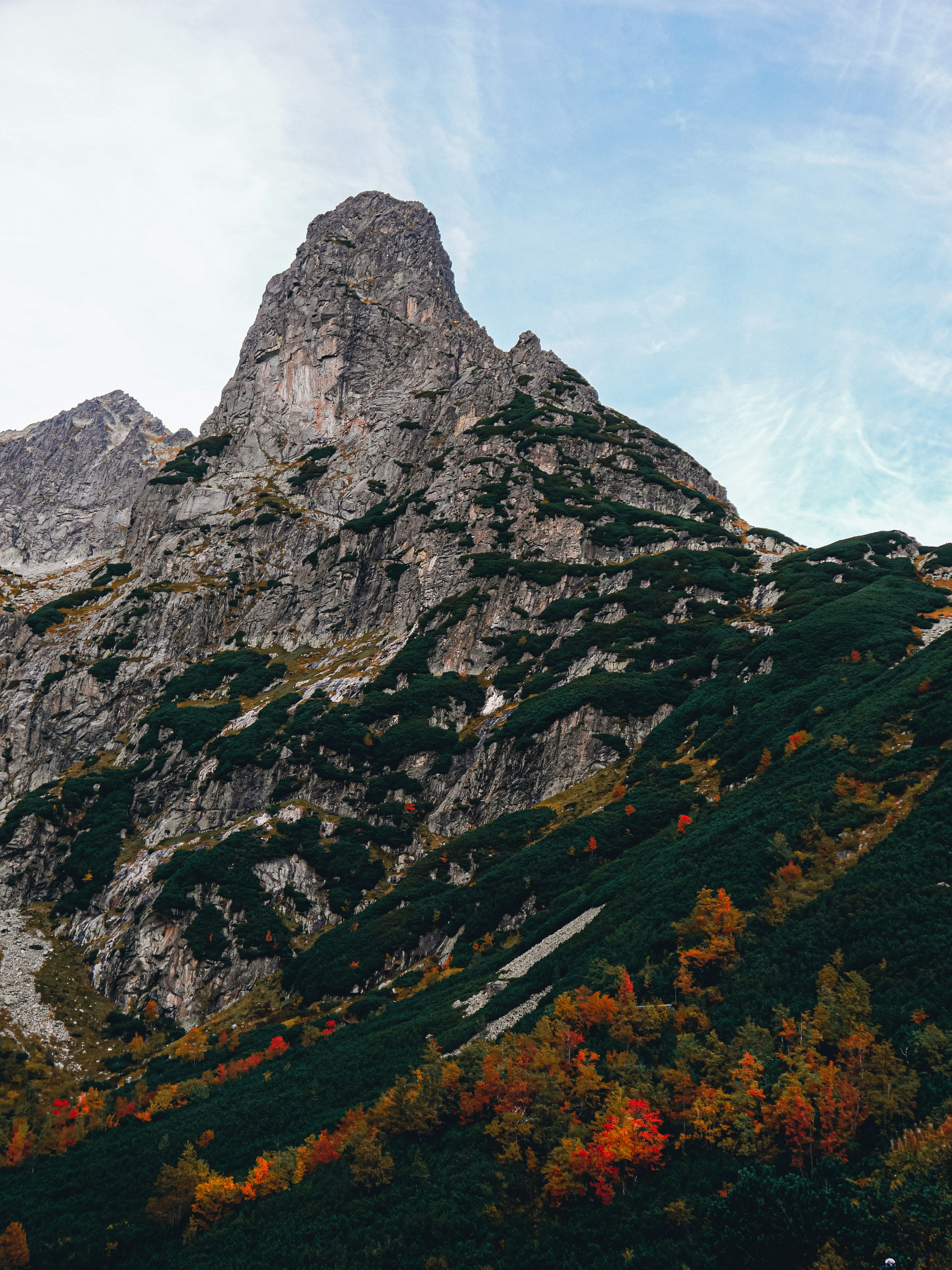 Jagged mountain peak with autumn foliage below.