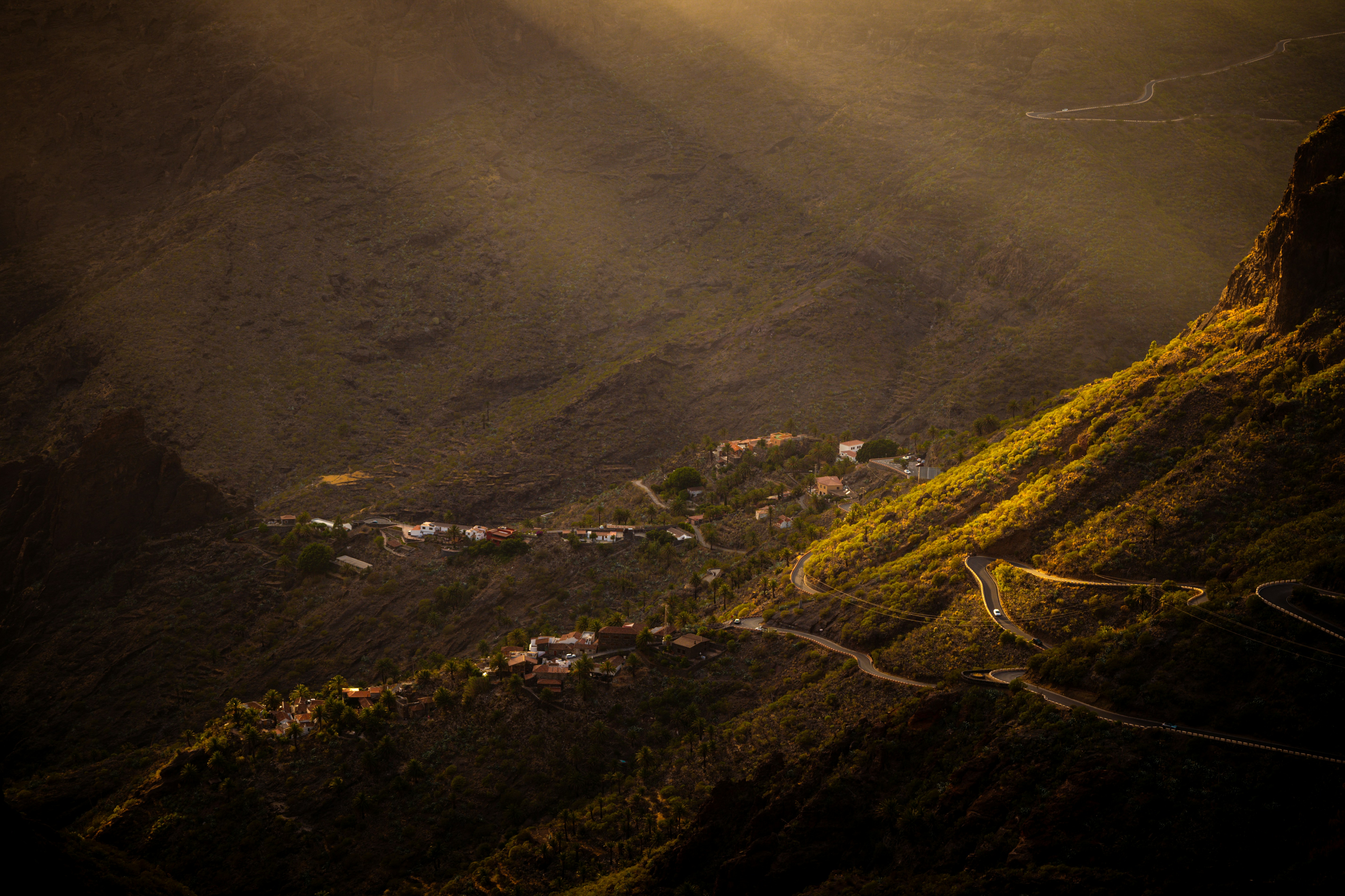 Sunlight streams through mountains onto a village.