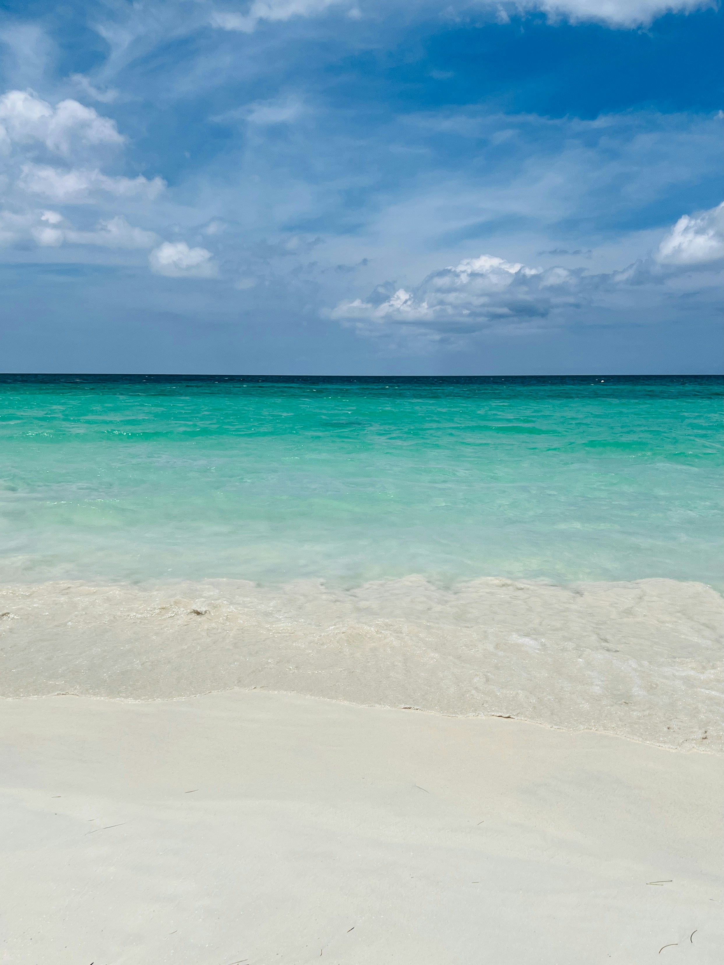 Turquoise ocean waves meet a white sandy beach.