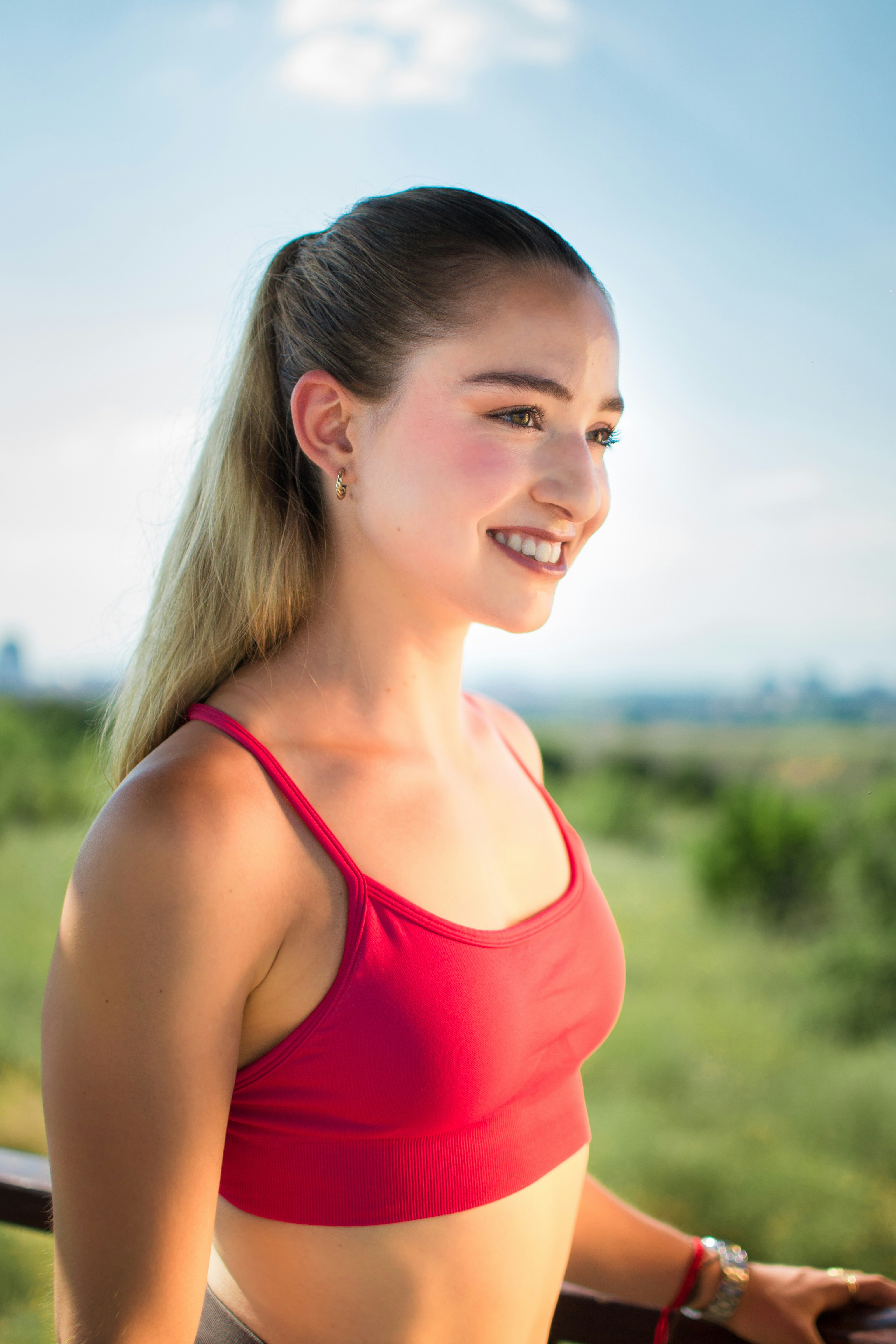 Young woman in red sports bra smiles outdoors