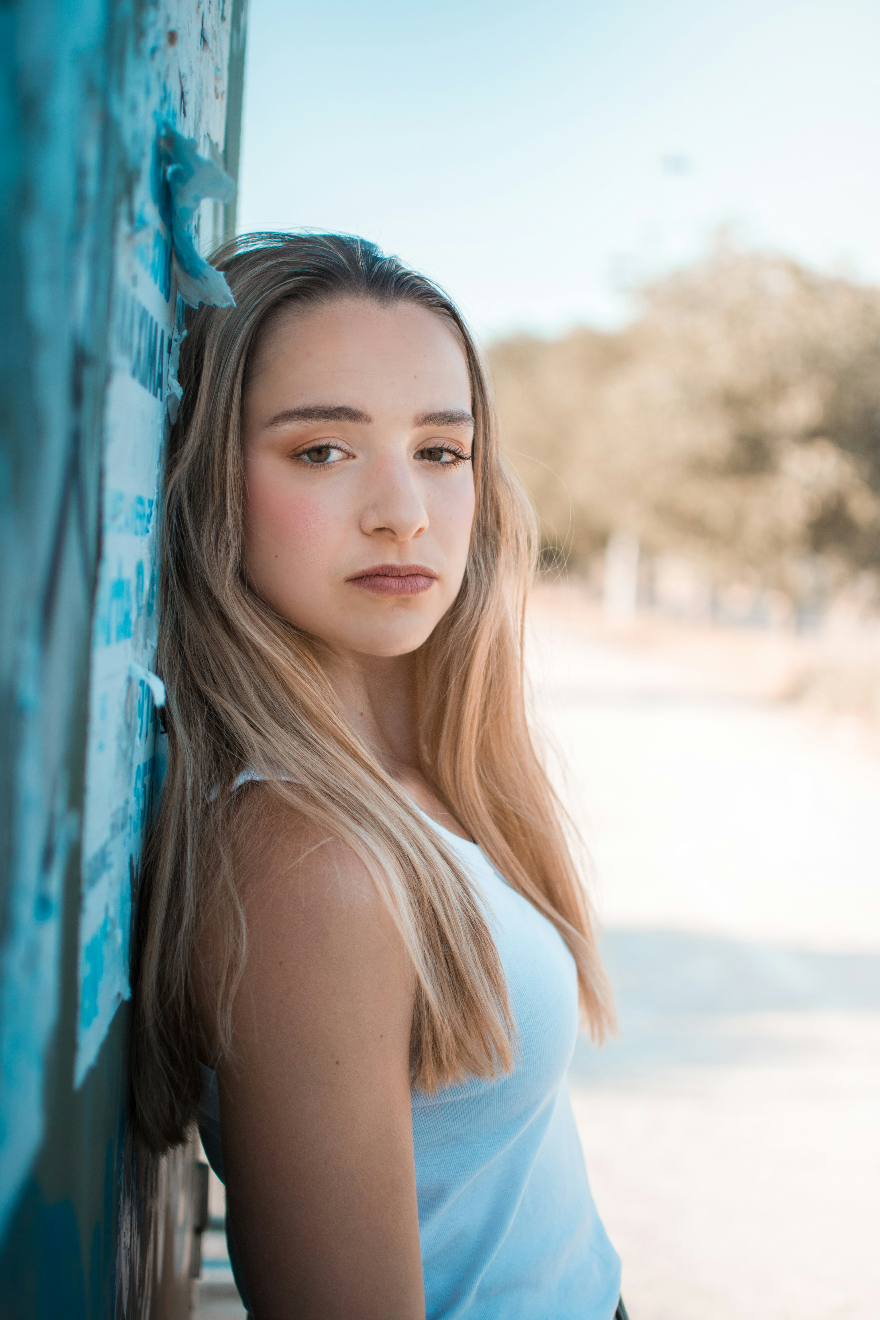 Young woman with blonde hair leaning against wall