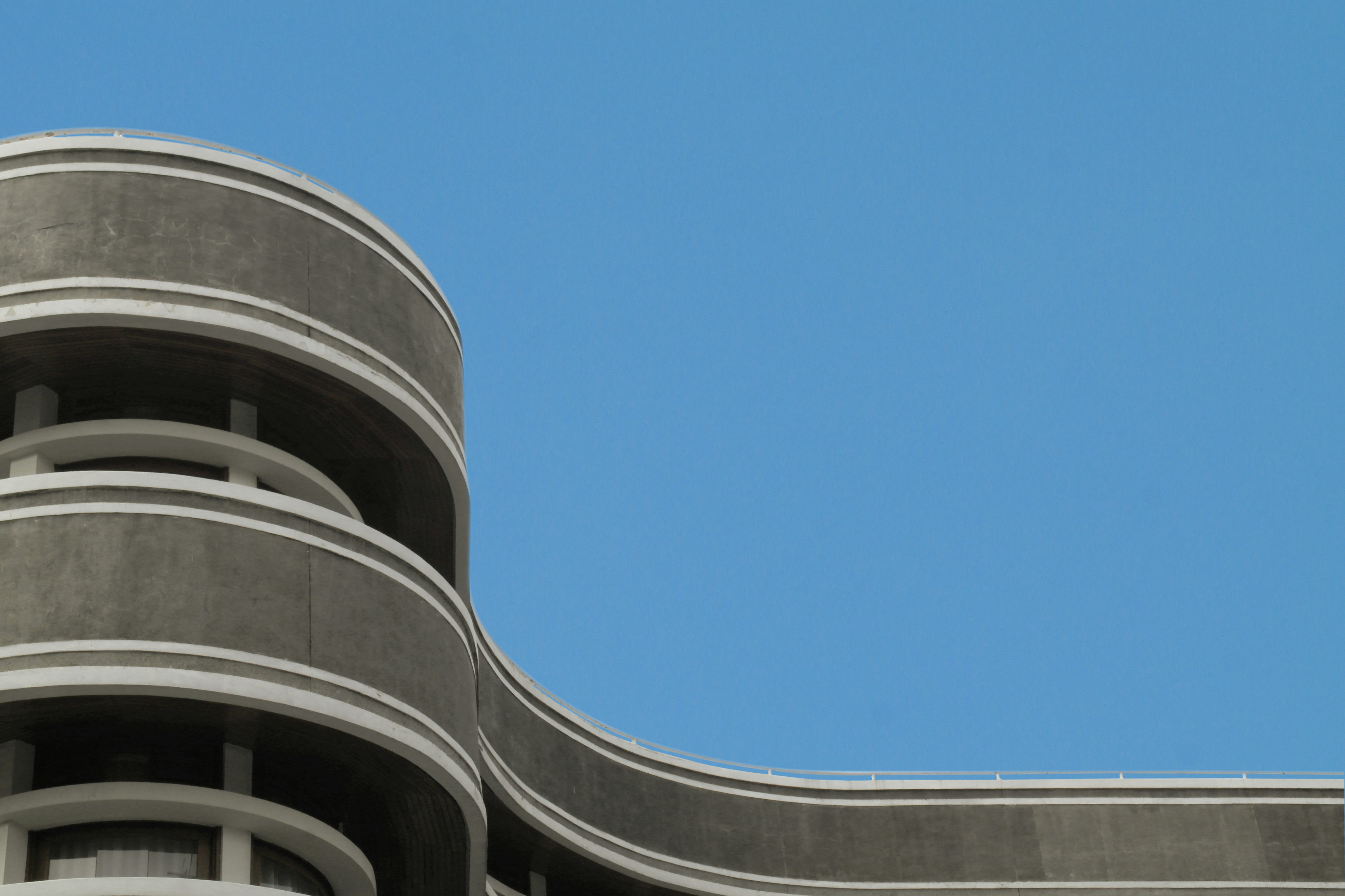 Savoy Homann hotel in Bandung, Indonesia | Curved concrete building against a clear blue sky.