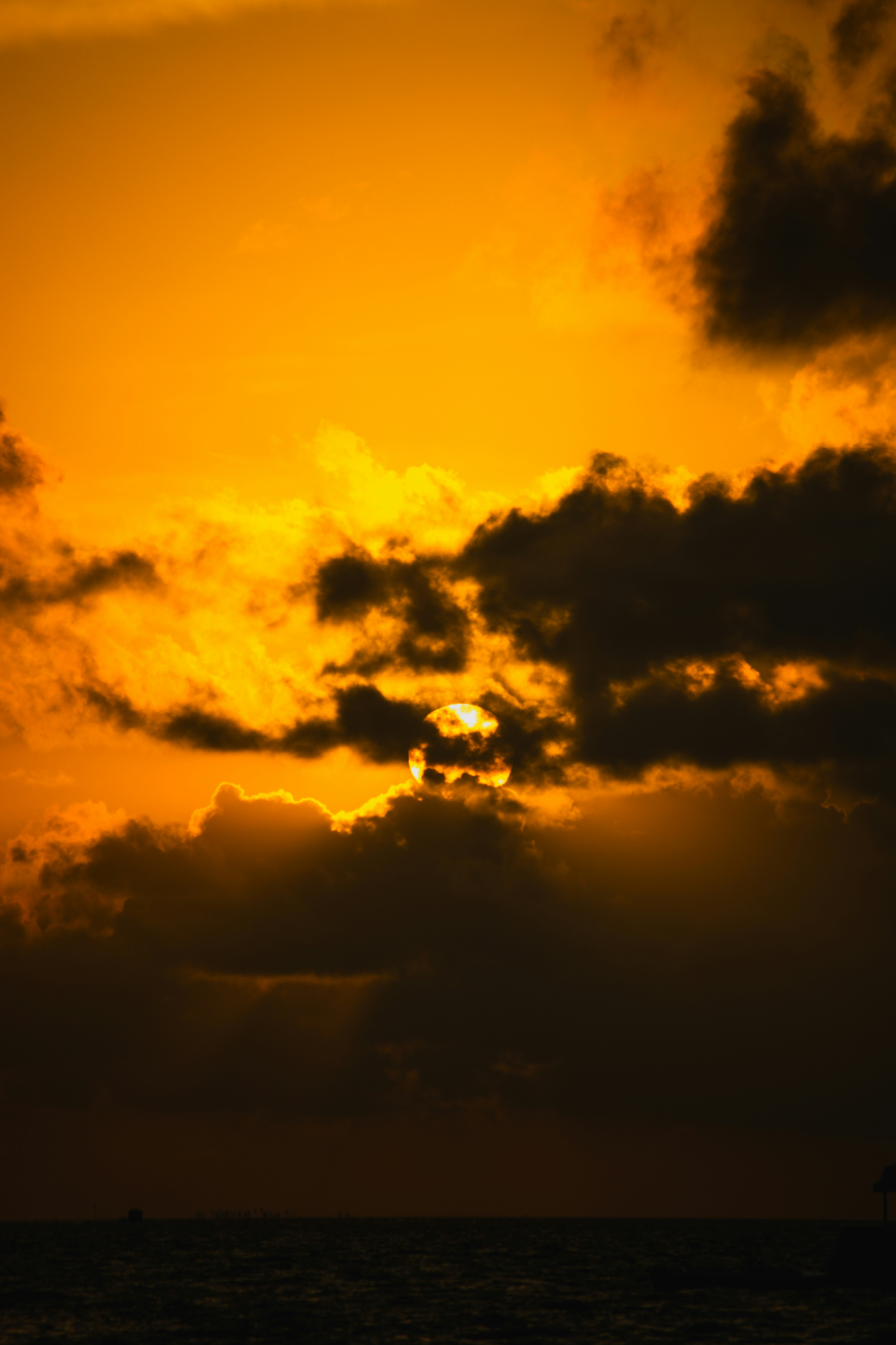 Sun setting behind dark clouds over ocean