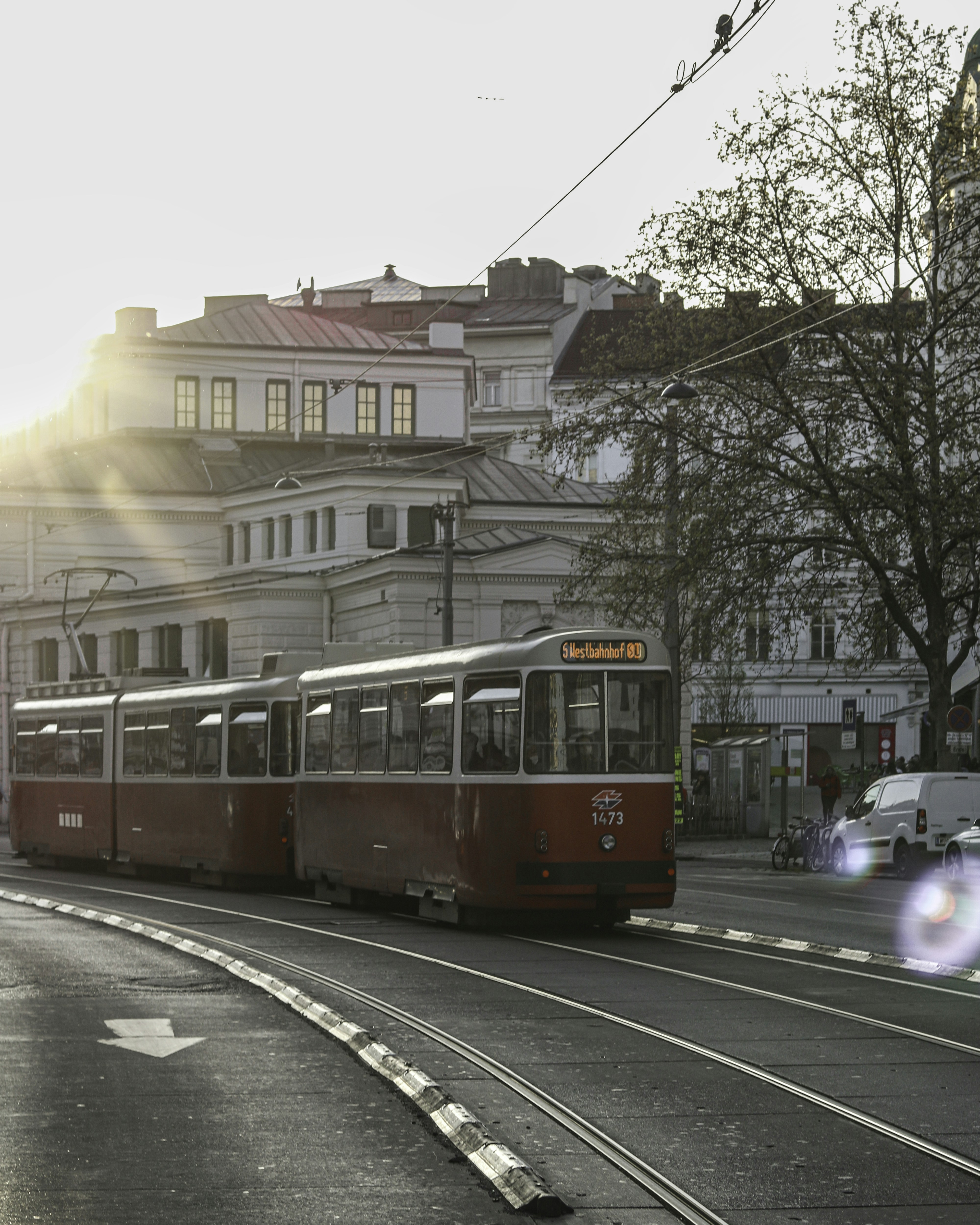 Red tram on city street at sunset