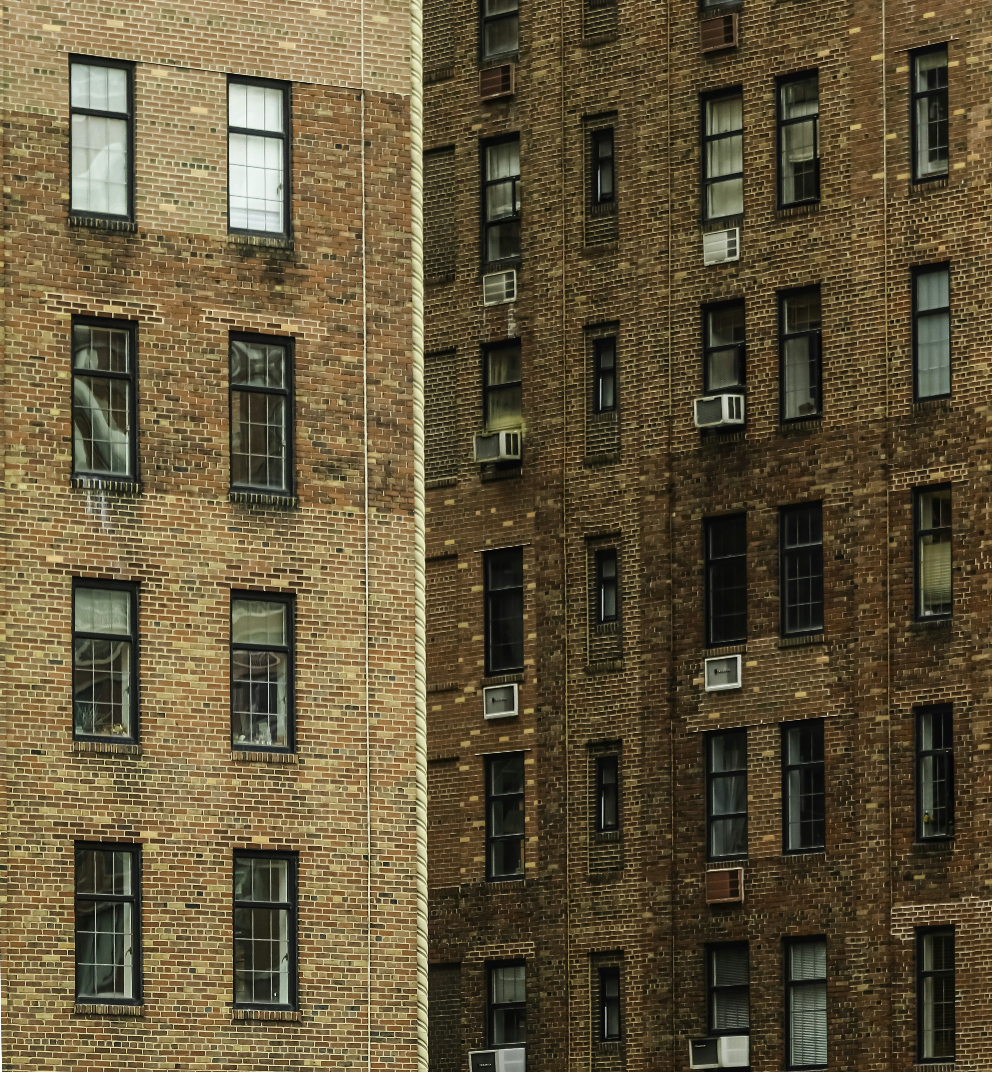 Two brick buildings with many windows and air conditioners.