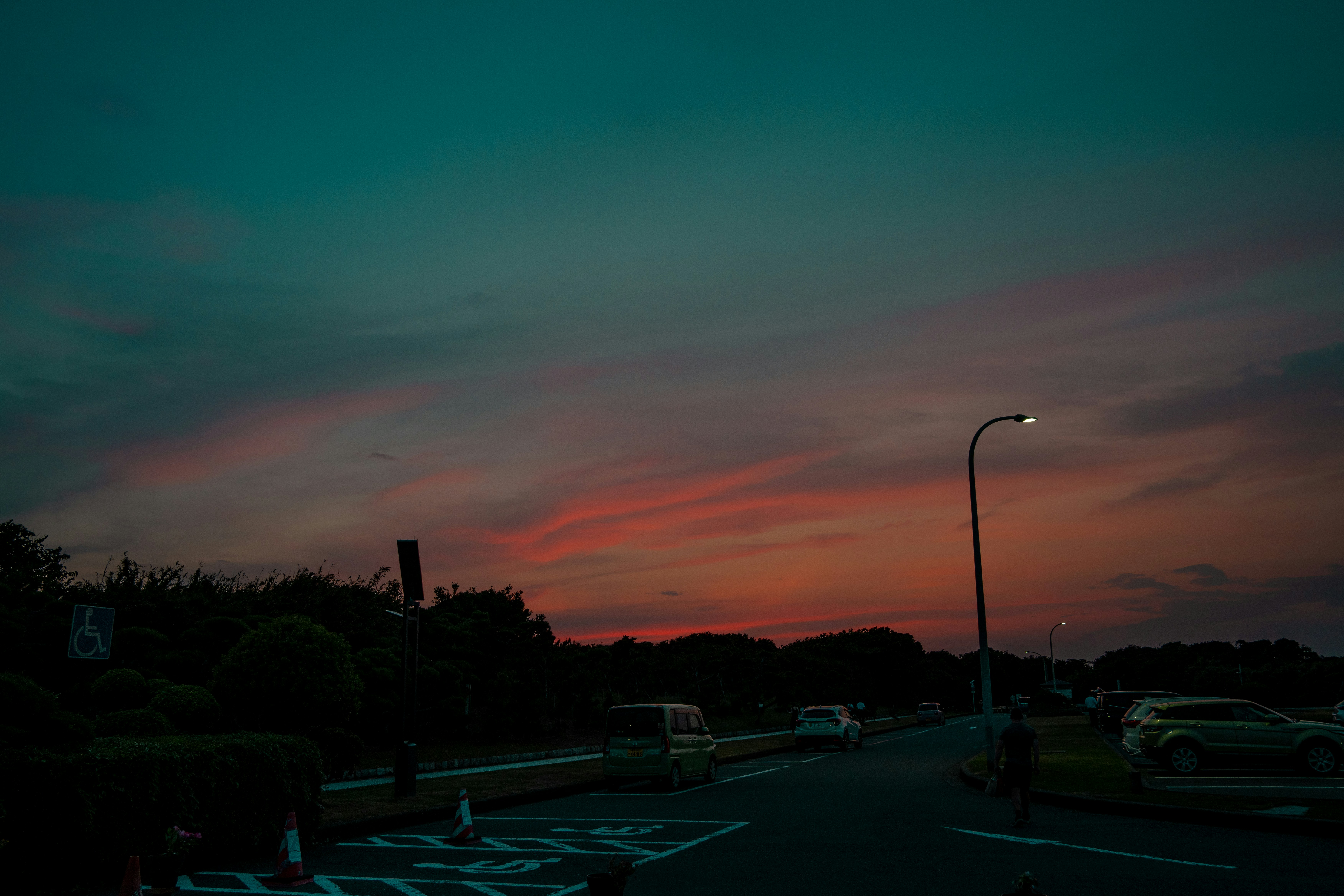 Dramatic sunset sky over a dark landscape with streetlights.