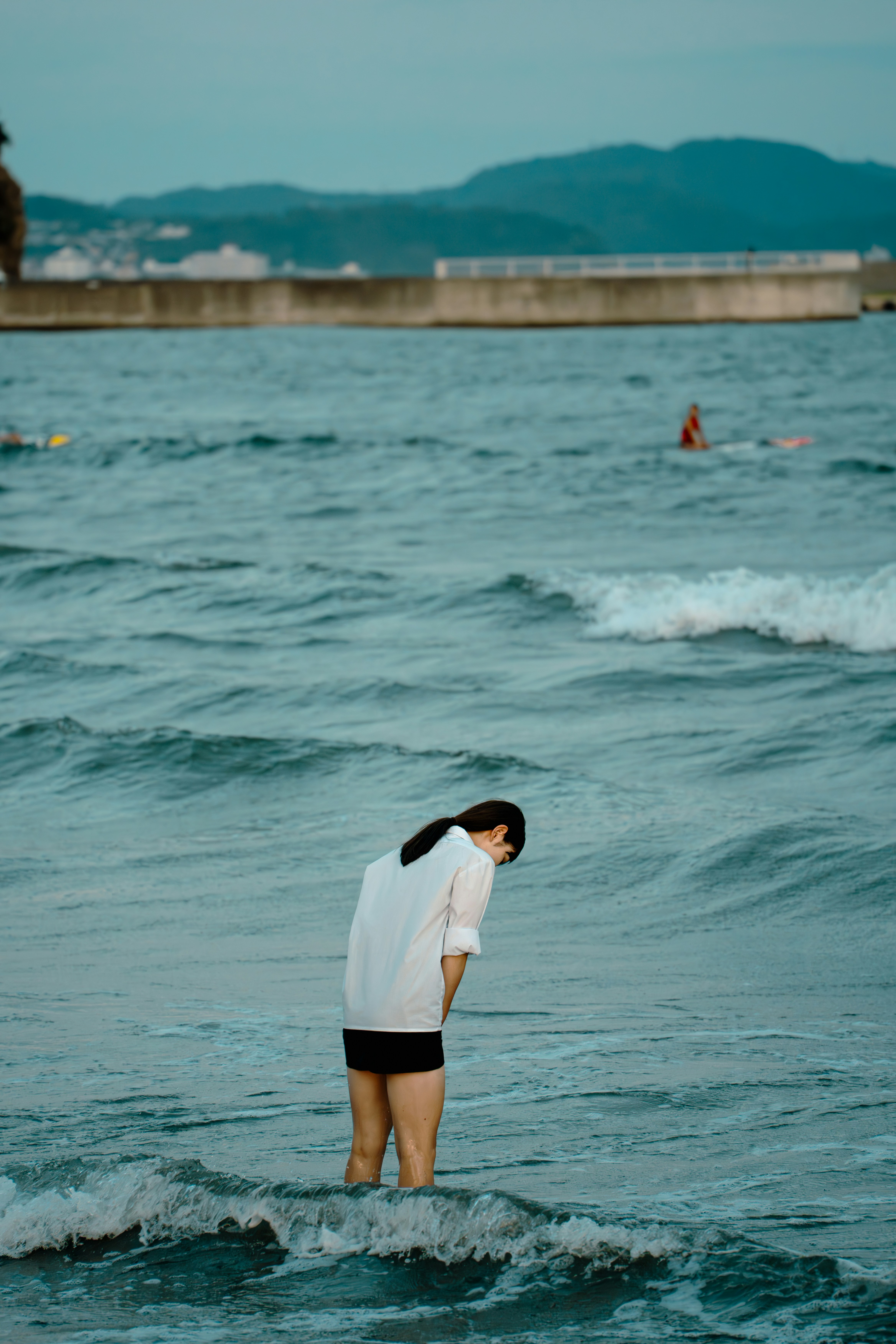 Woman in white shirt standing in the ocean waves