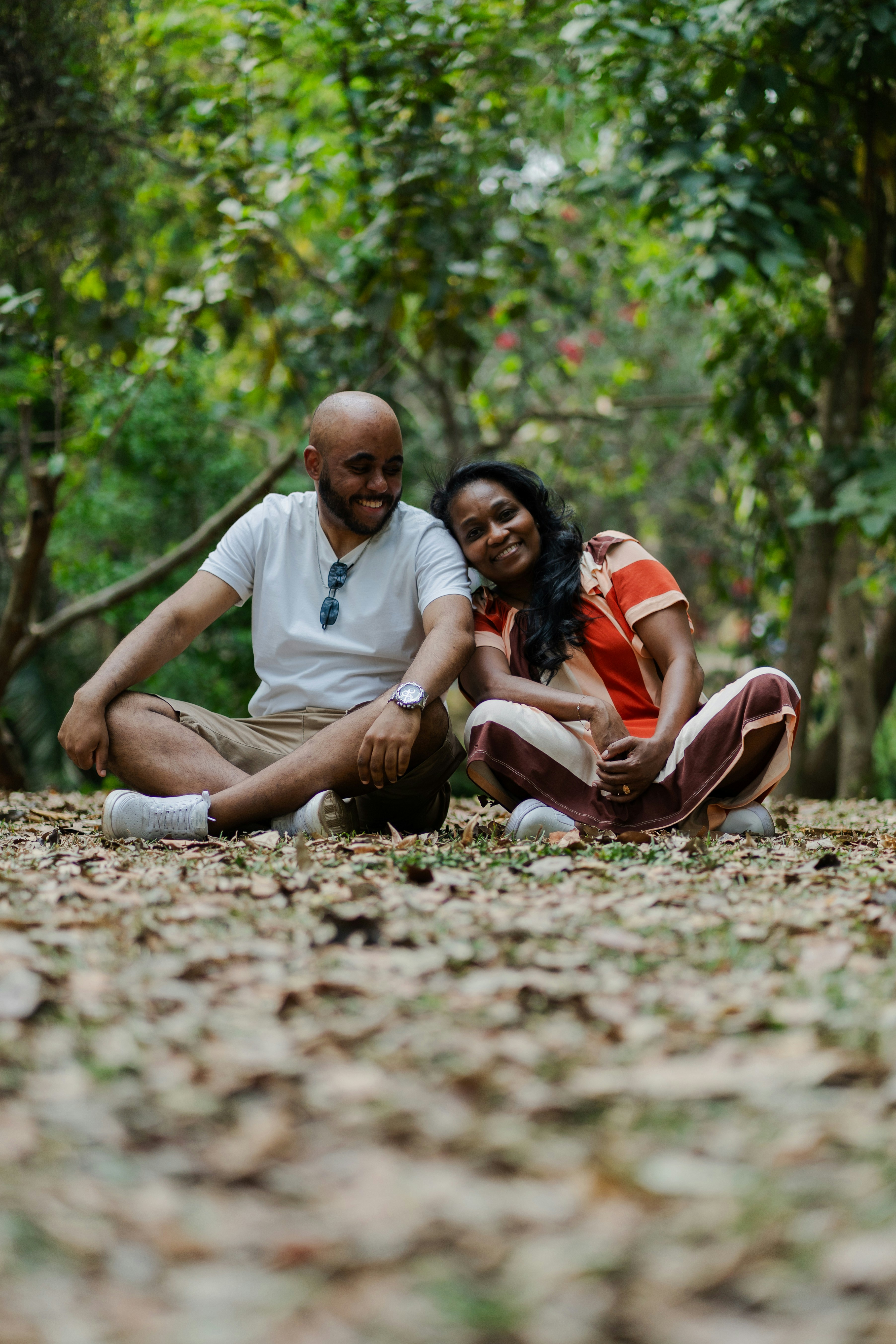 A couple sitting on the ground in a park.