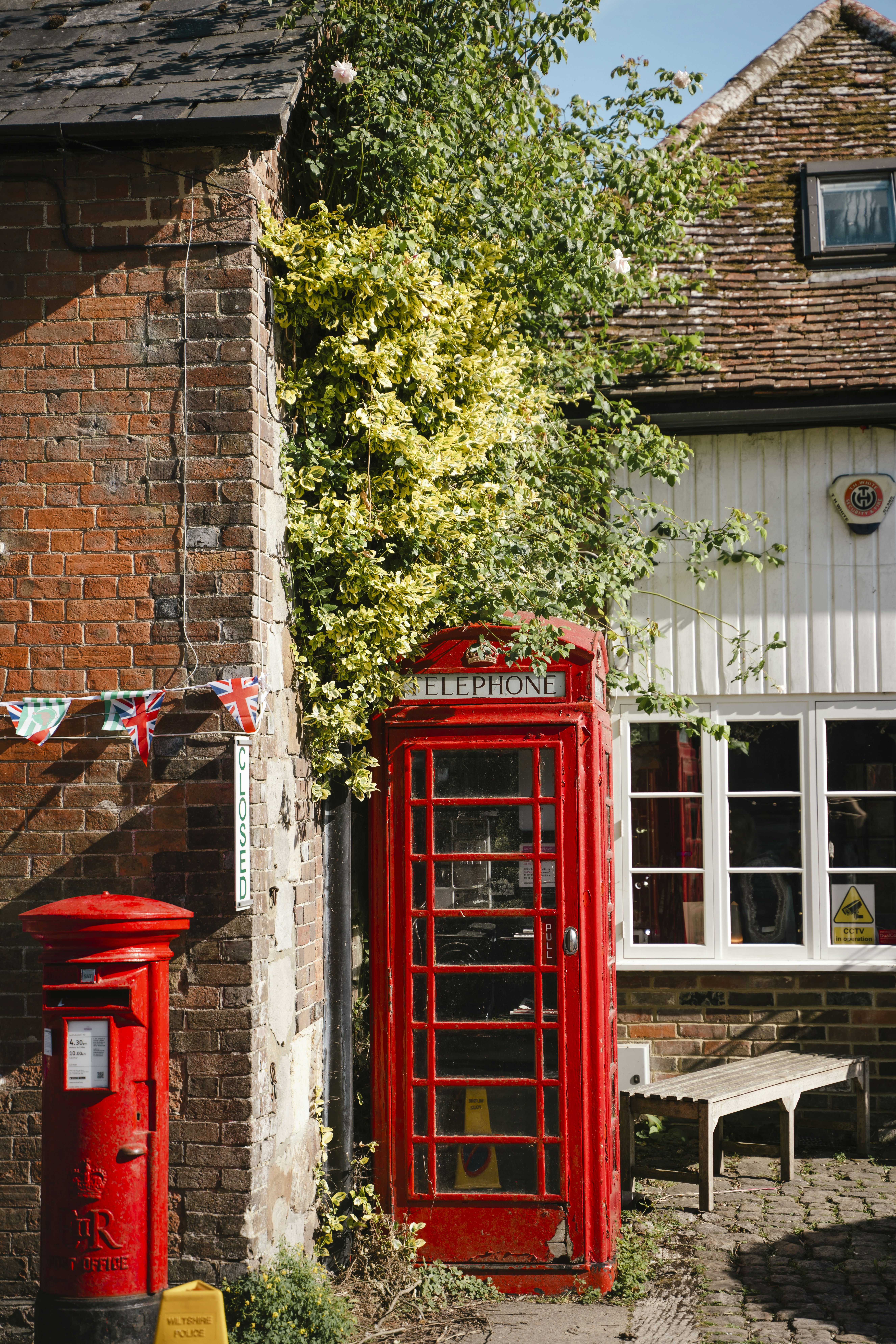 Red telephone box and post box beside brick building.