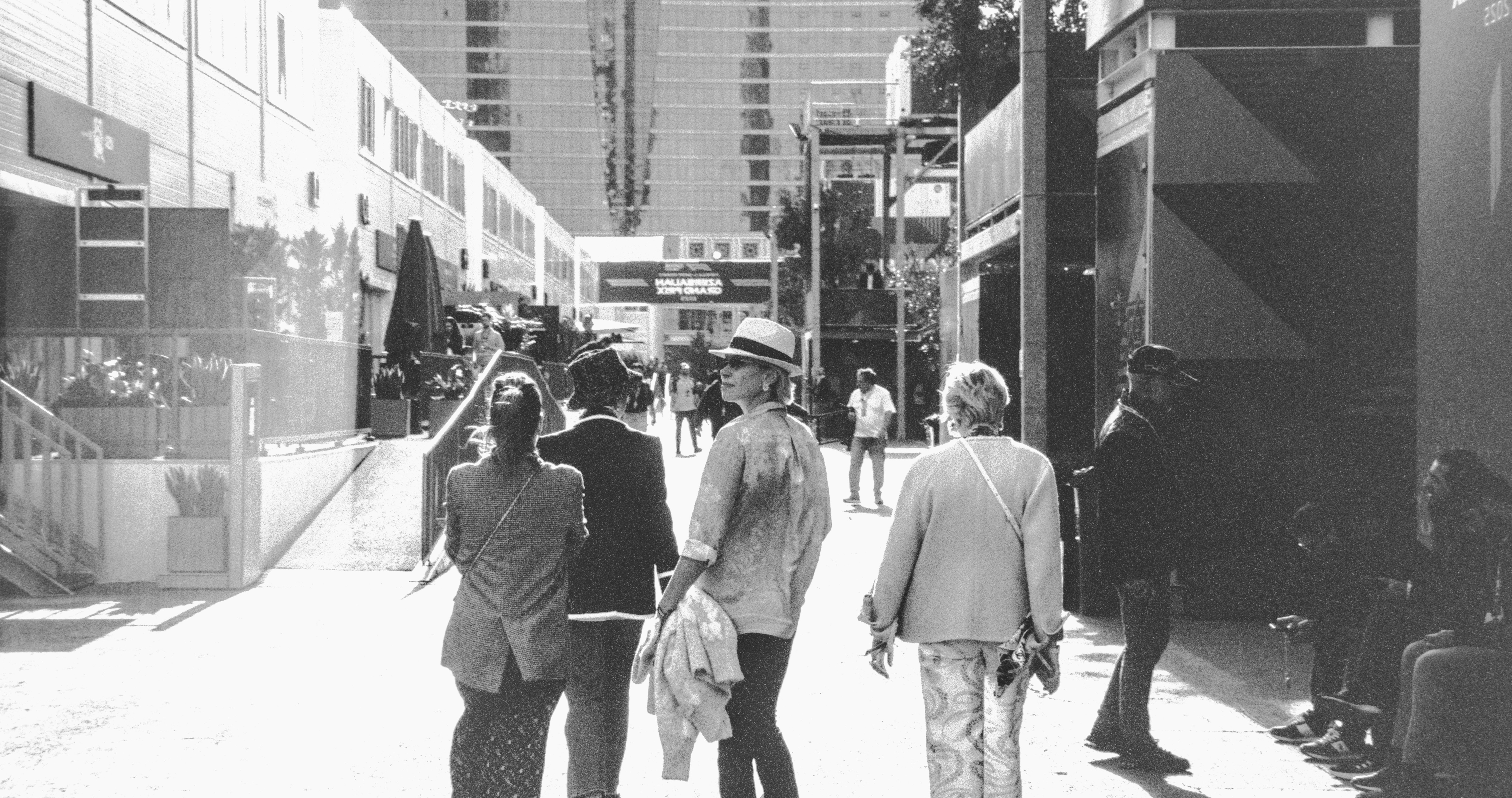 Four individuals walking together in a bustling urban environment, surrounded by modern architecture and a lively atmosphere.