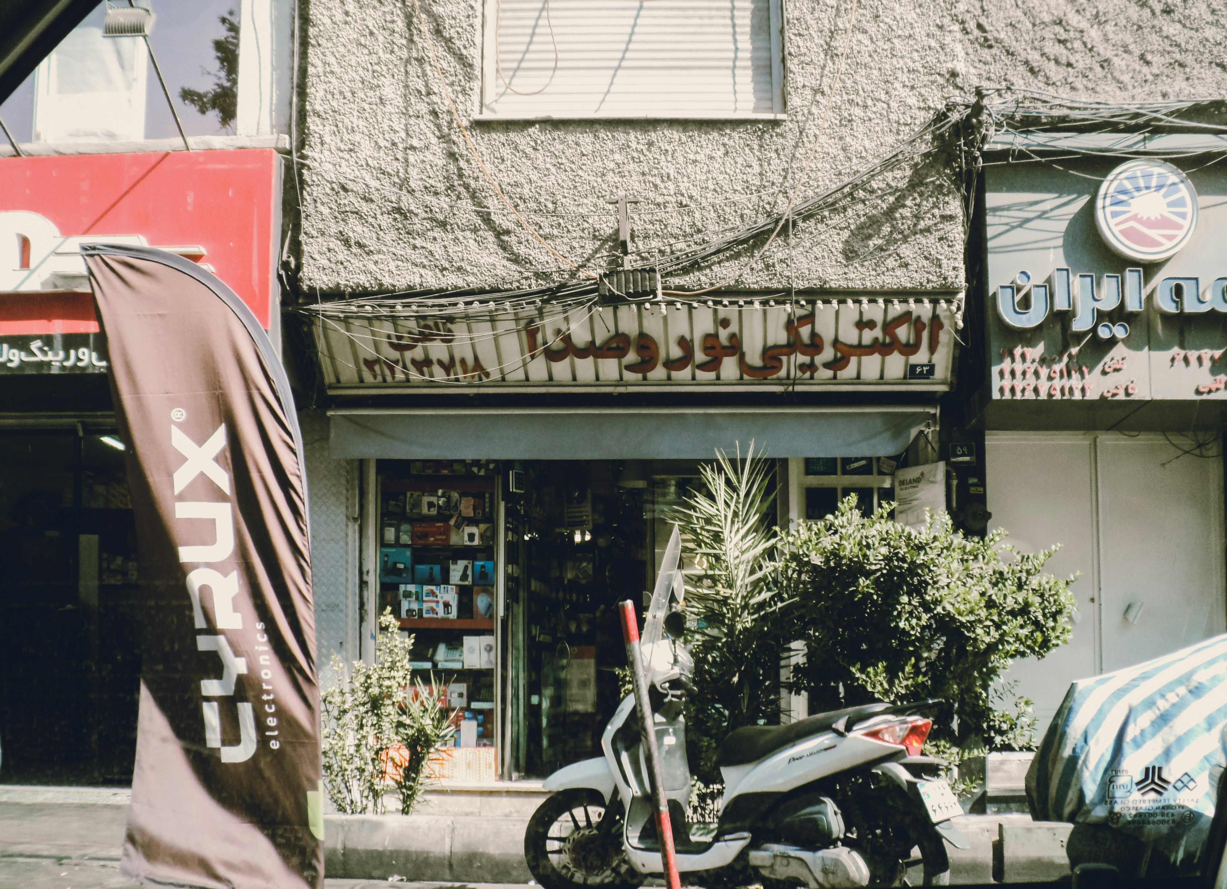 Light and Sound, tangled in wires. | A scooter parked outside a small shop with signage.
