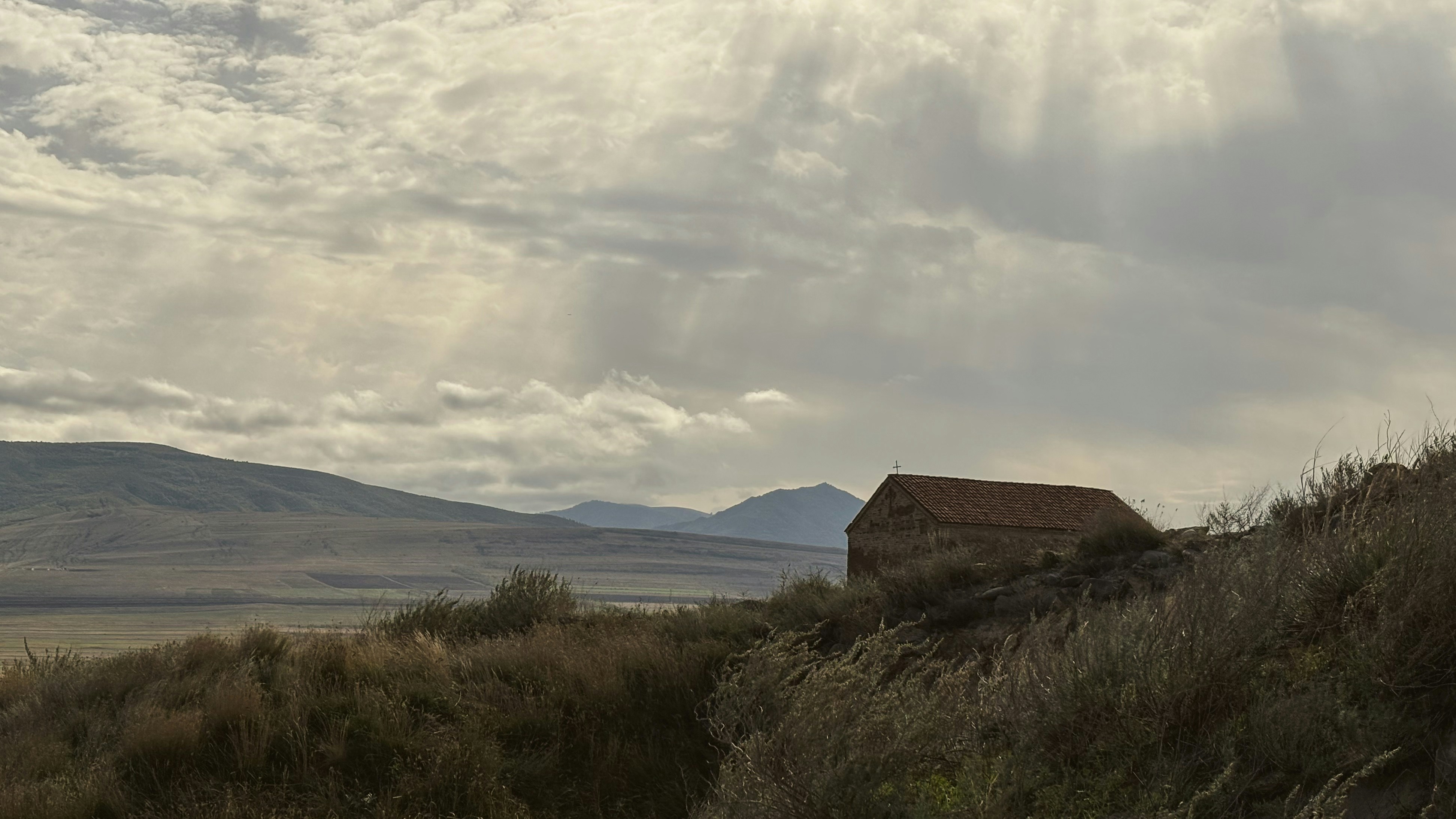 Abandoned structure nestled among rolling hills under a moody sky, evoking a sense of nostalgia and solitude.