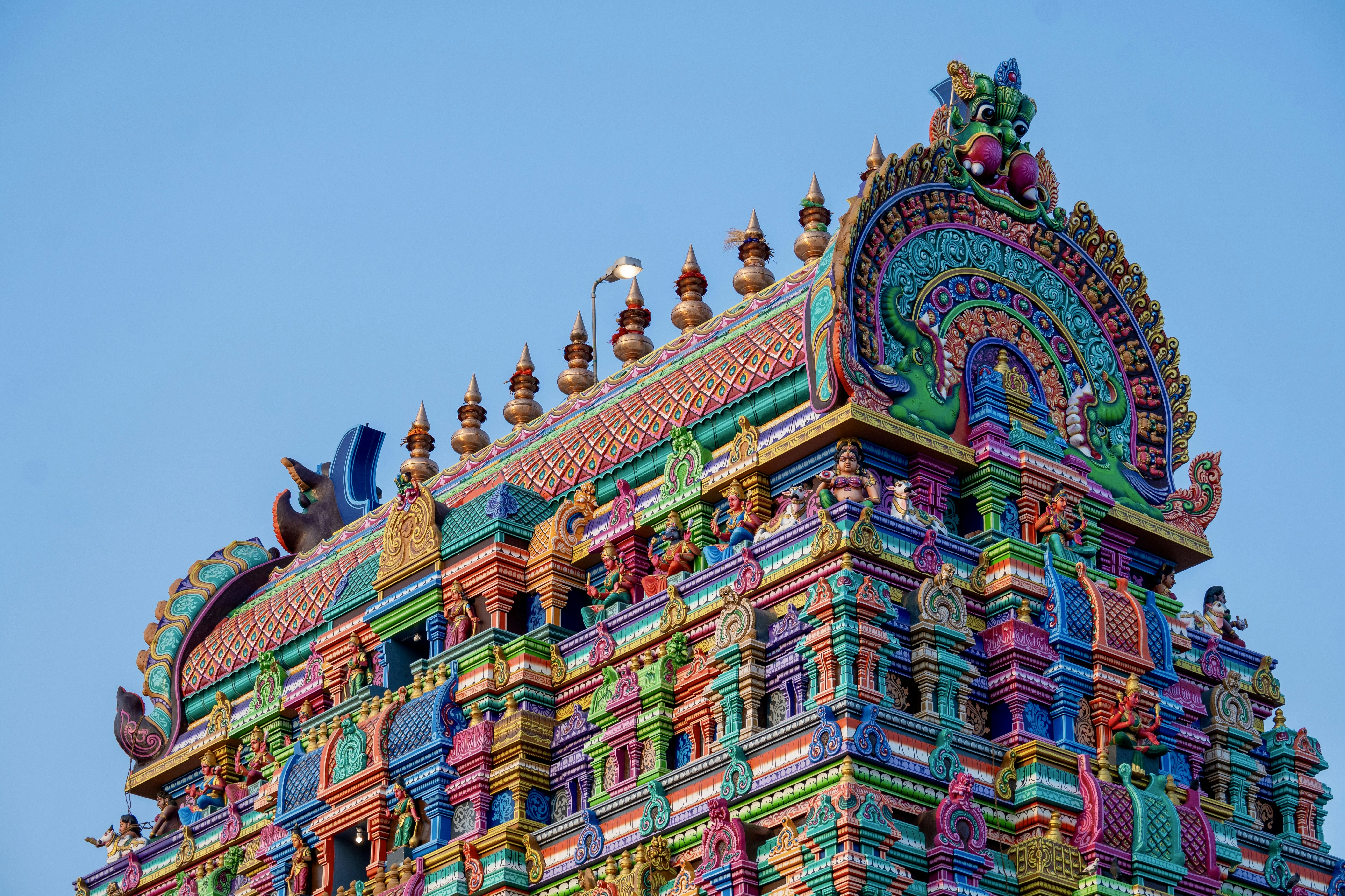 Colorful hindu temple tower against a clear blue sky.
