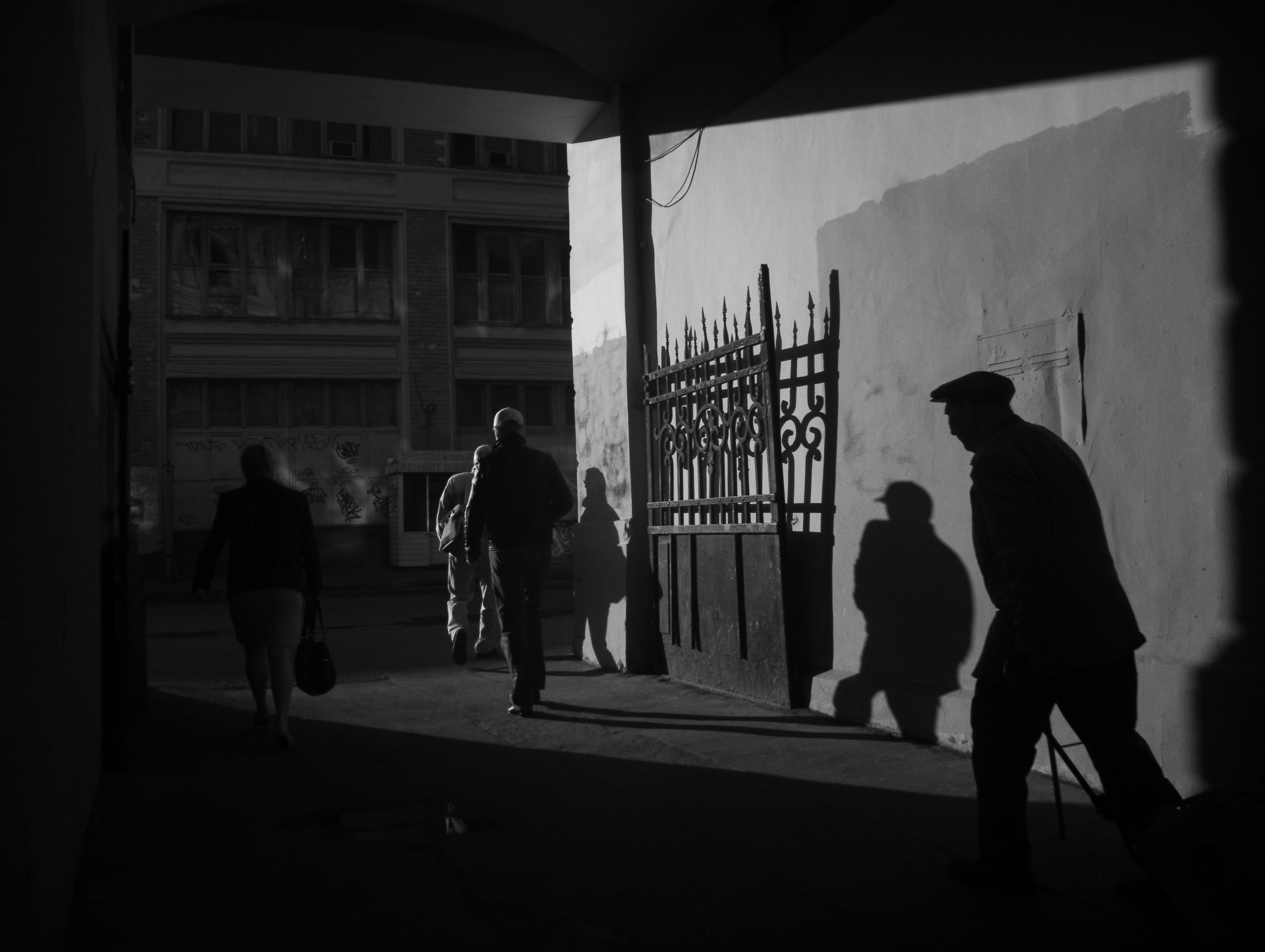 Silhouetted figures walk towards a gate at dusk.