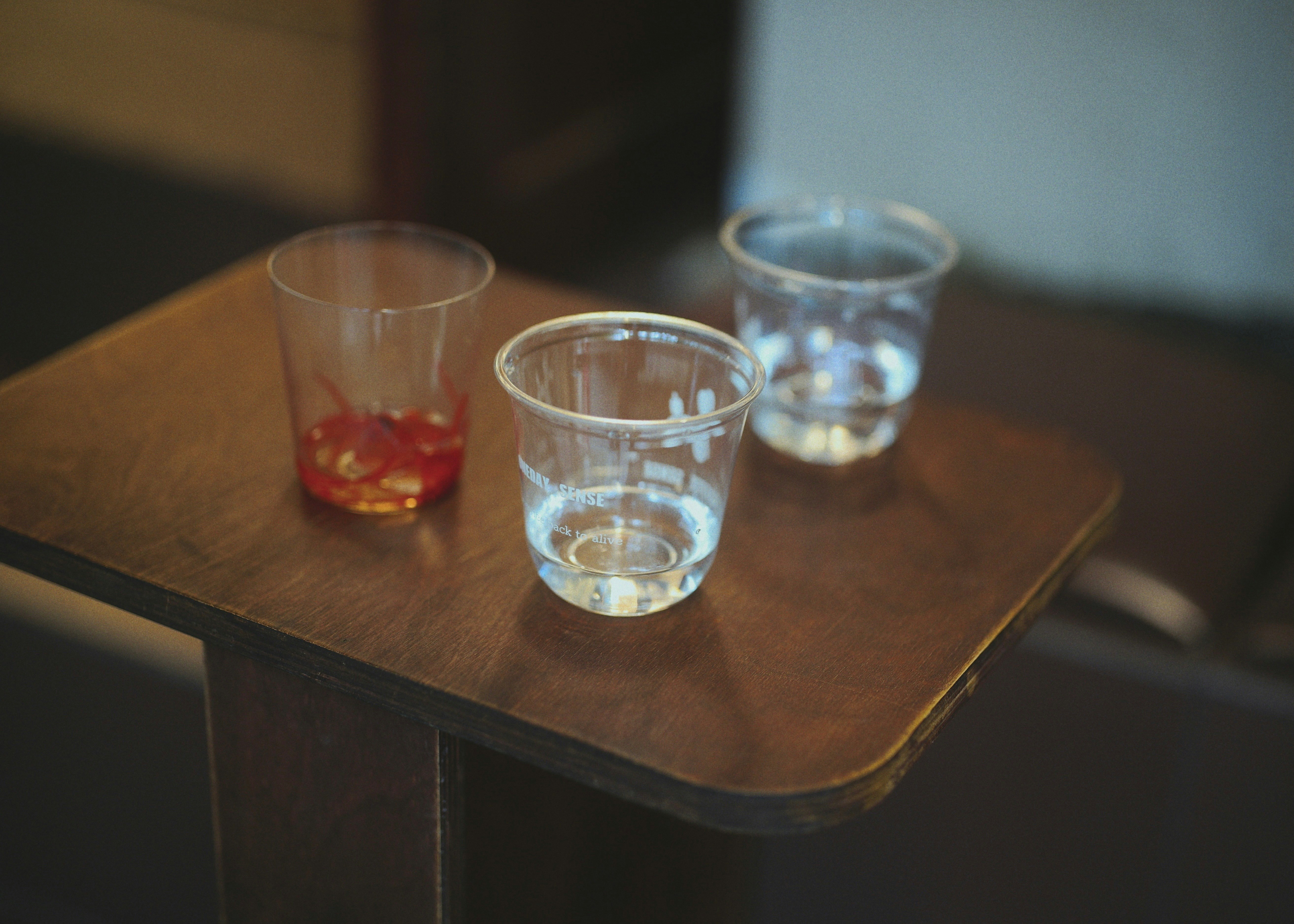 Three clear cups with liquid on a table.