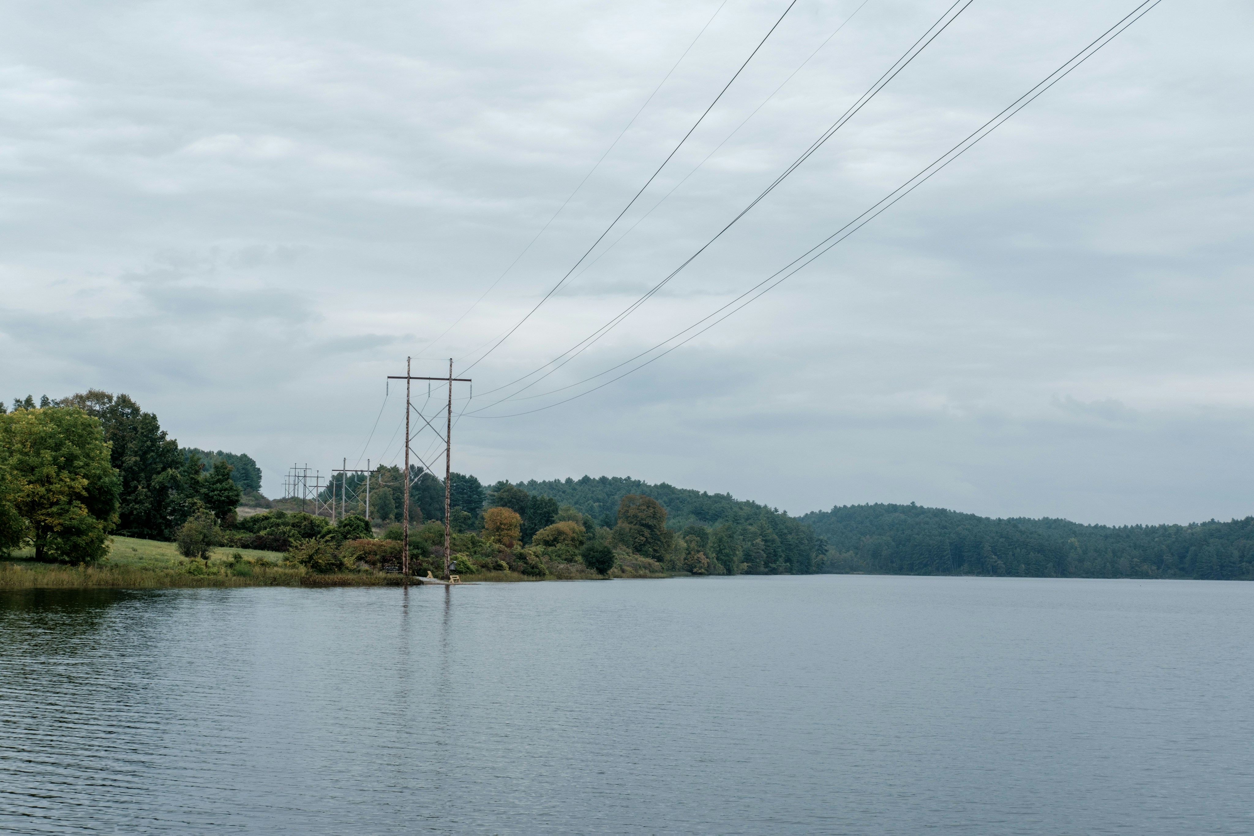 Power lines cross a calm lake under cloudy skies. photo – Free Forest ...