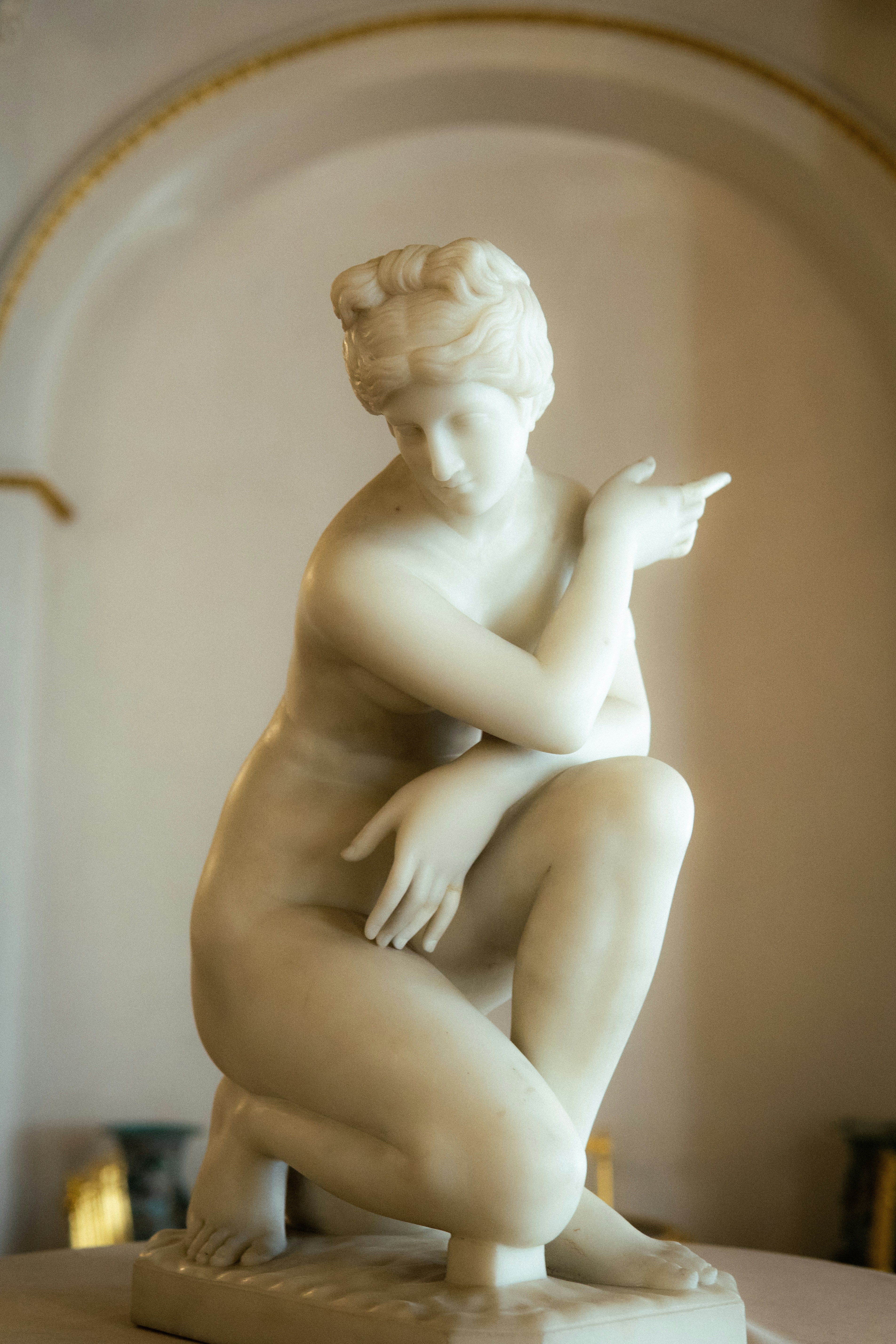 Marble sculpture of a kneeling woman pointing.
