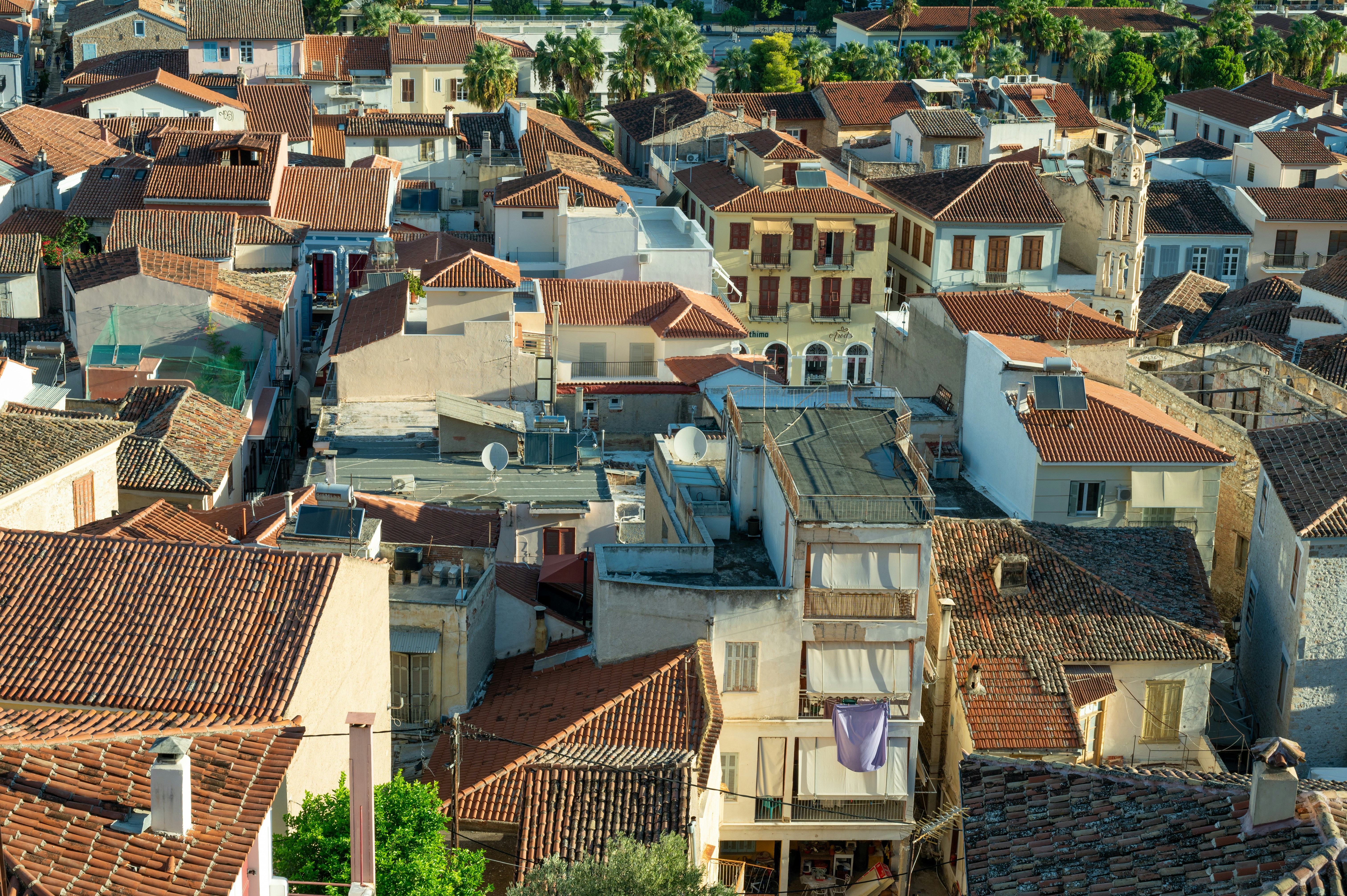 Sunlit rooftops and narrow streets in the charming old town of Nafplio, Greece. | Rooftops of a dense mediterranean town during daytime.