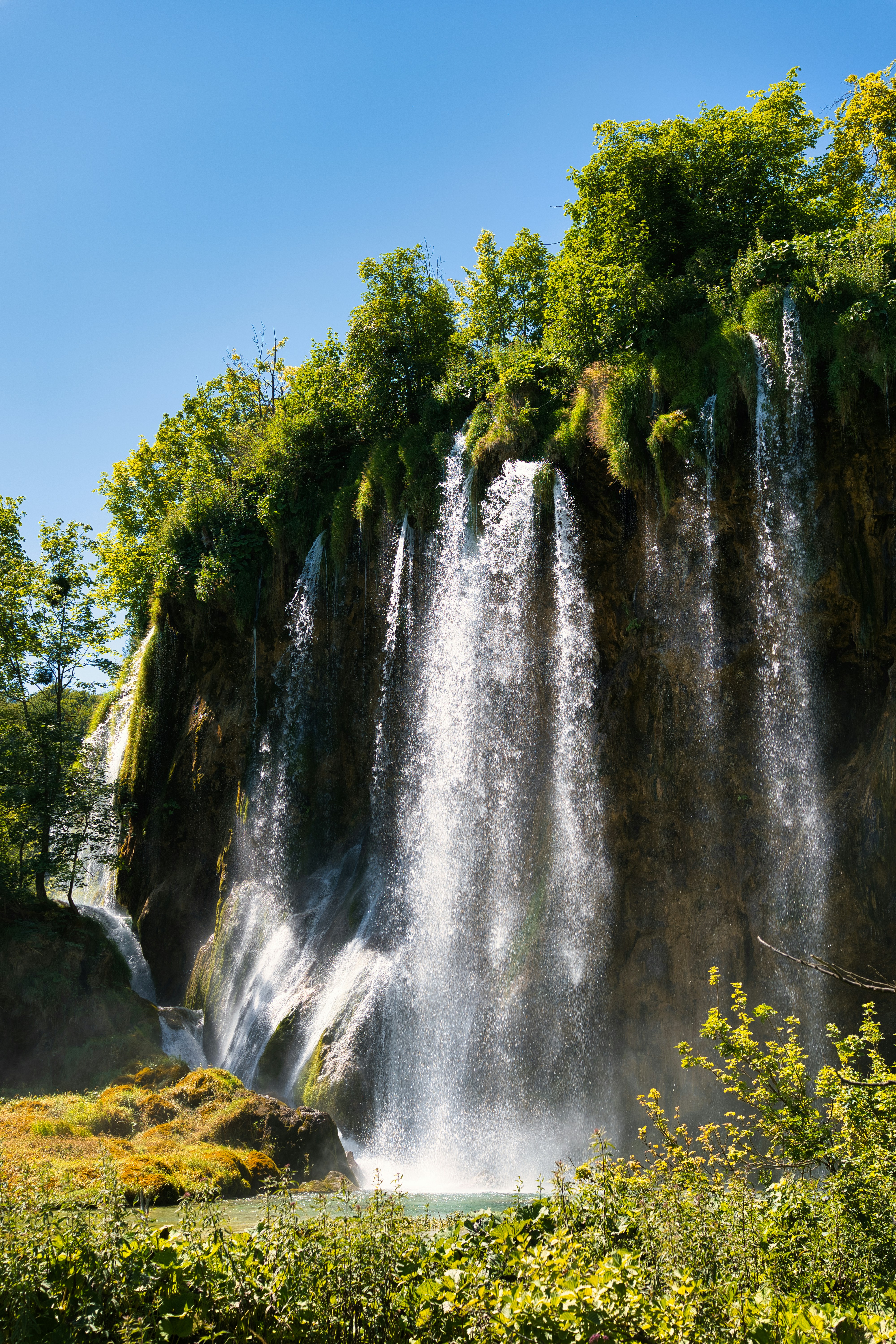 A lush waterfall cascades down a rocky cliffside.