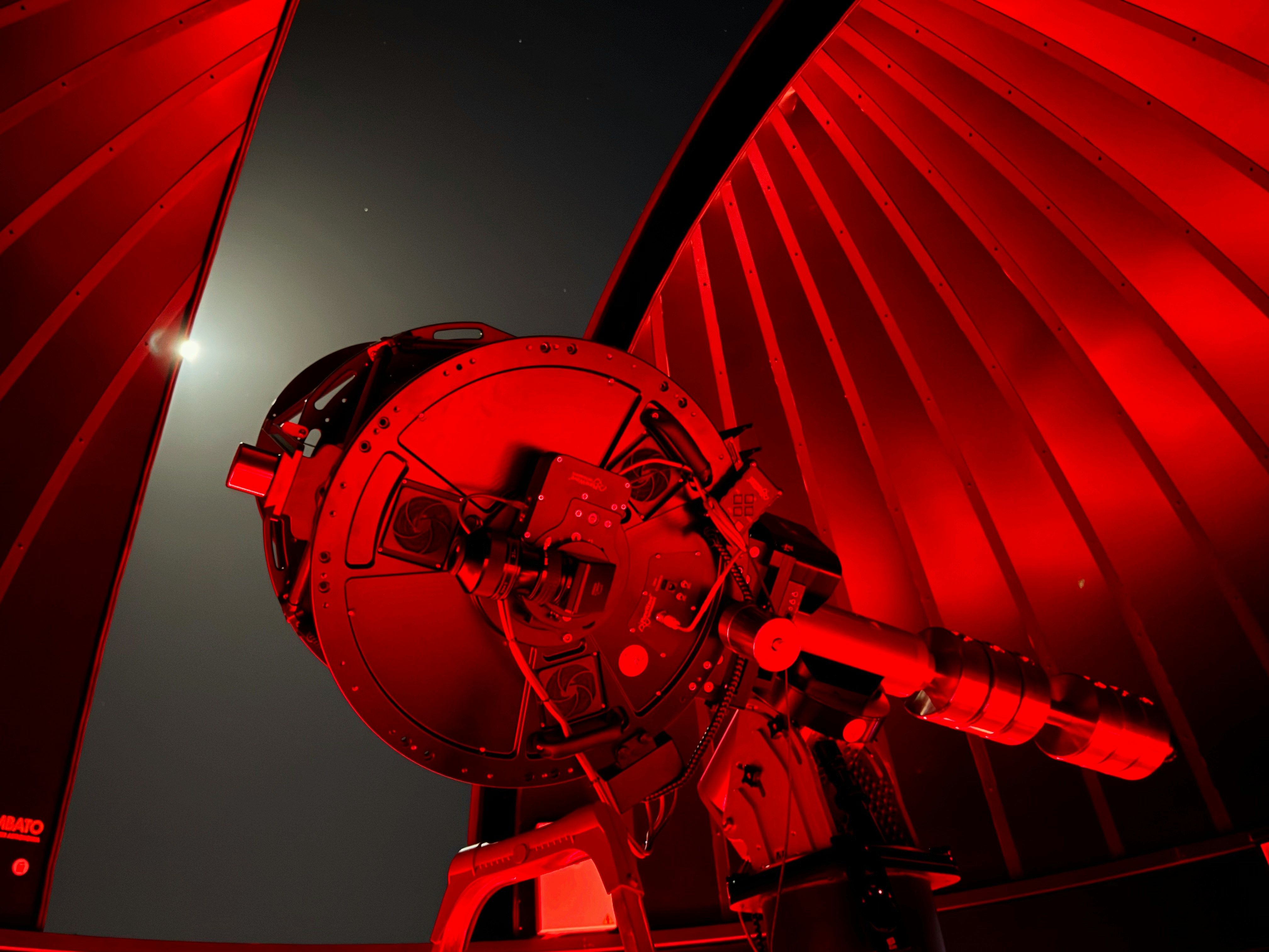 Telescope dome with red lights and moon visible moon
