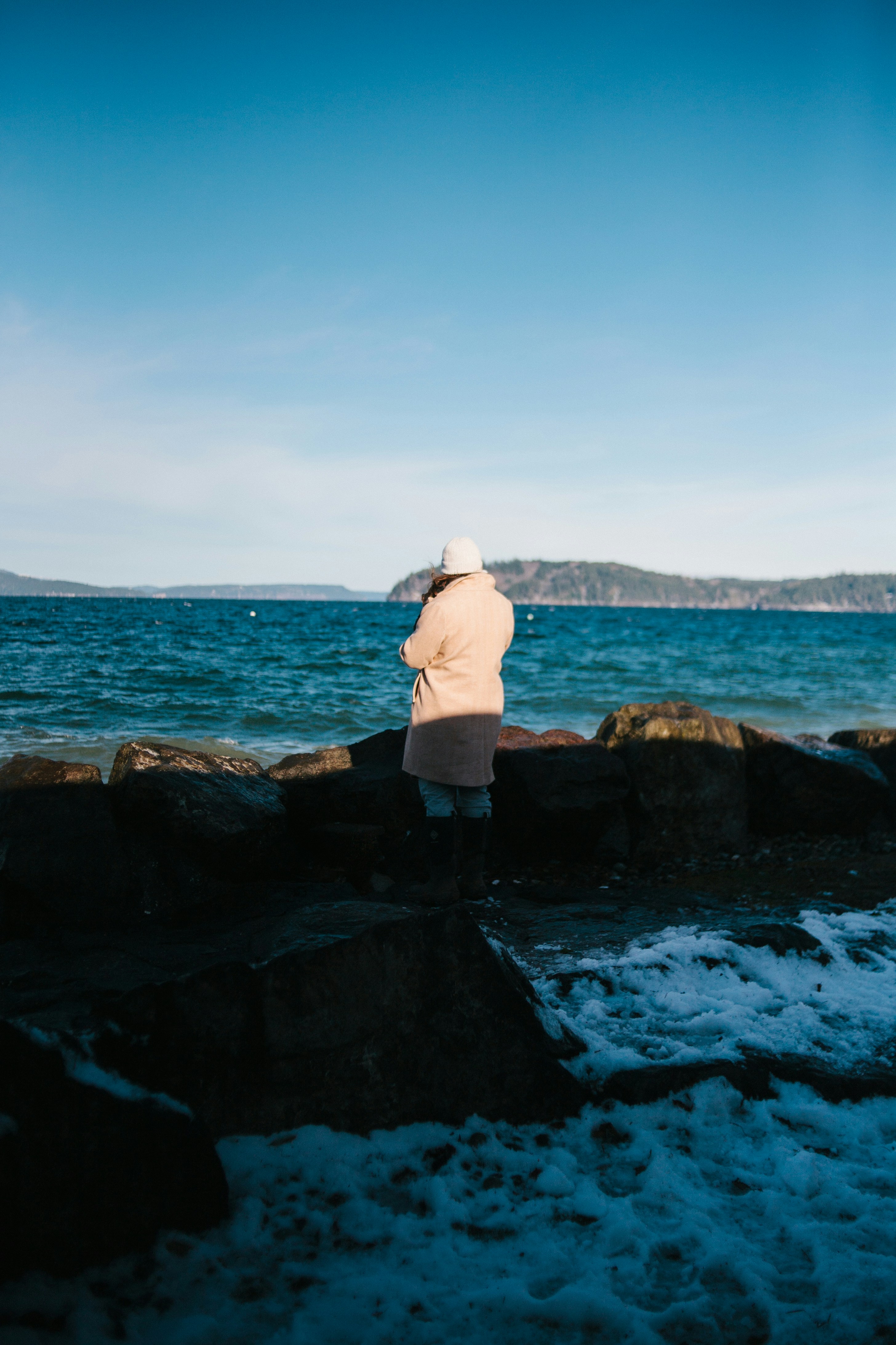 Woman in coat standing by the ocean