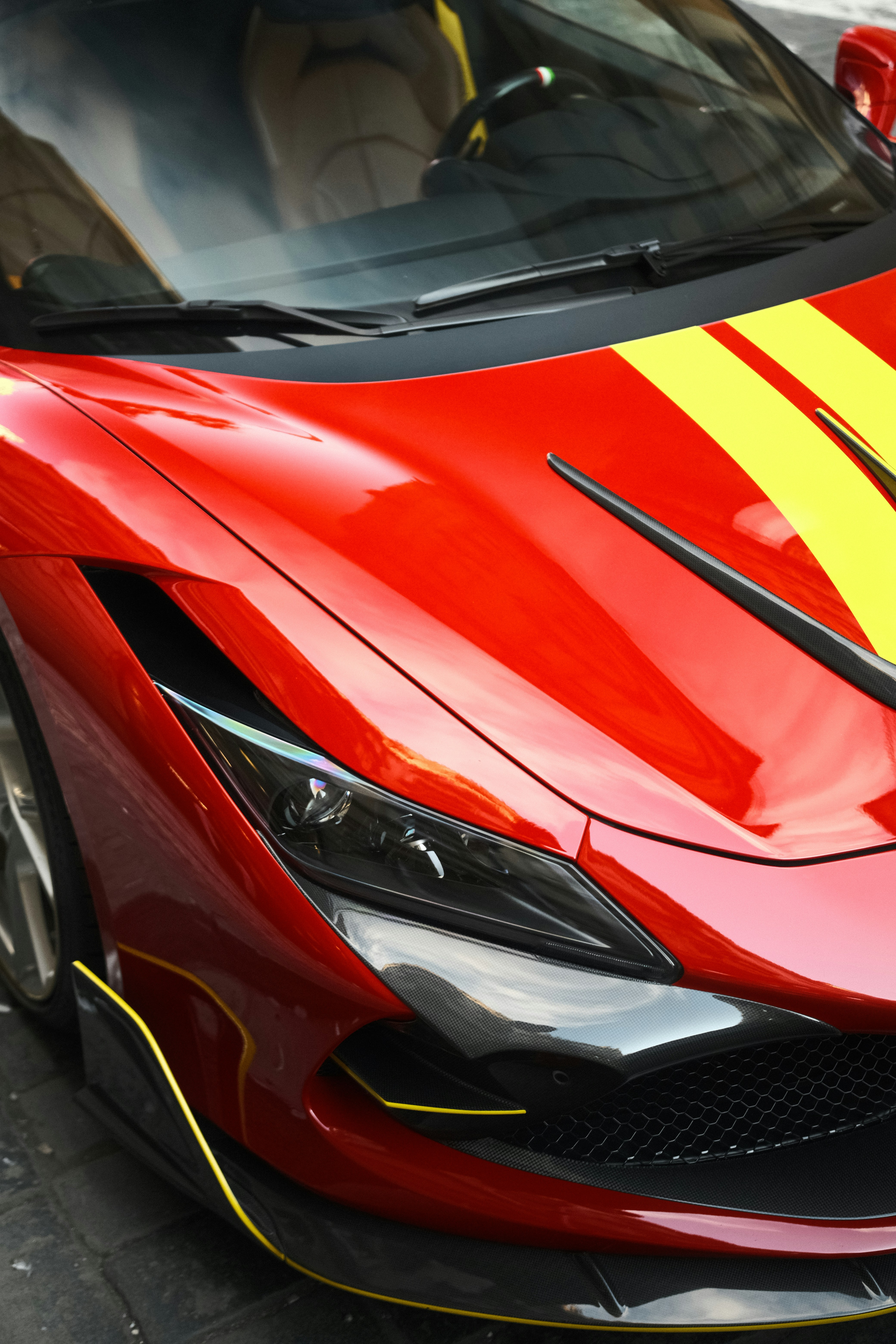 A close-up view of a sleek red sports car showcasing its aerodynamic lines and distinctive racing stripes. The image highlights the meticulous design and engineering of modern automotive artistry.