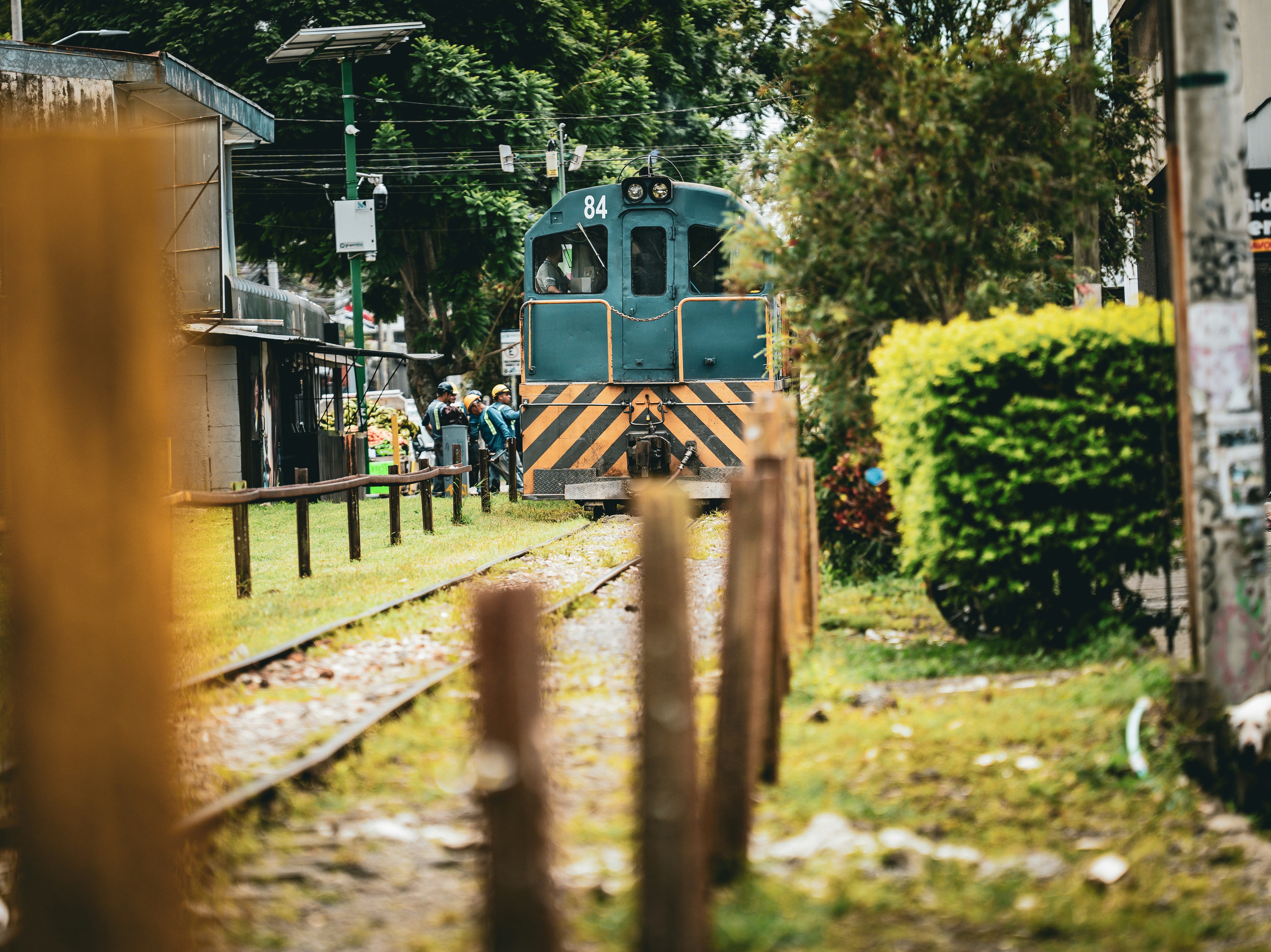 Par de una sesión de street photography en San Pedro, San José, Costa Rica | A teal train approaches a station platform.
