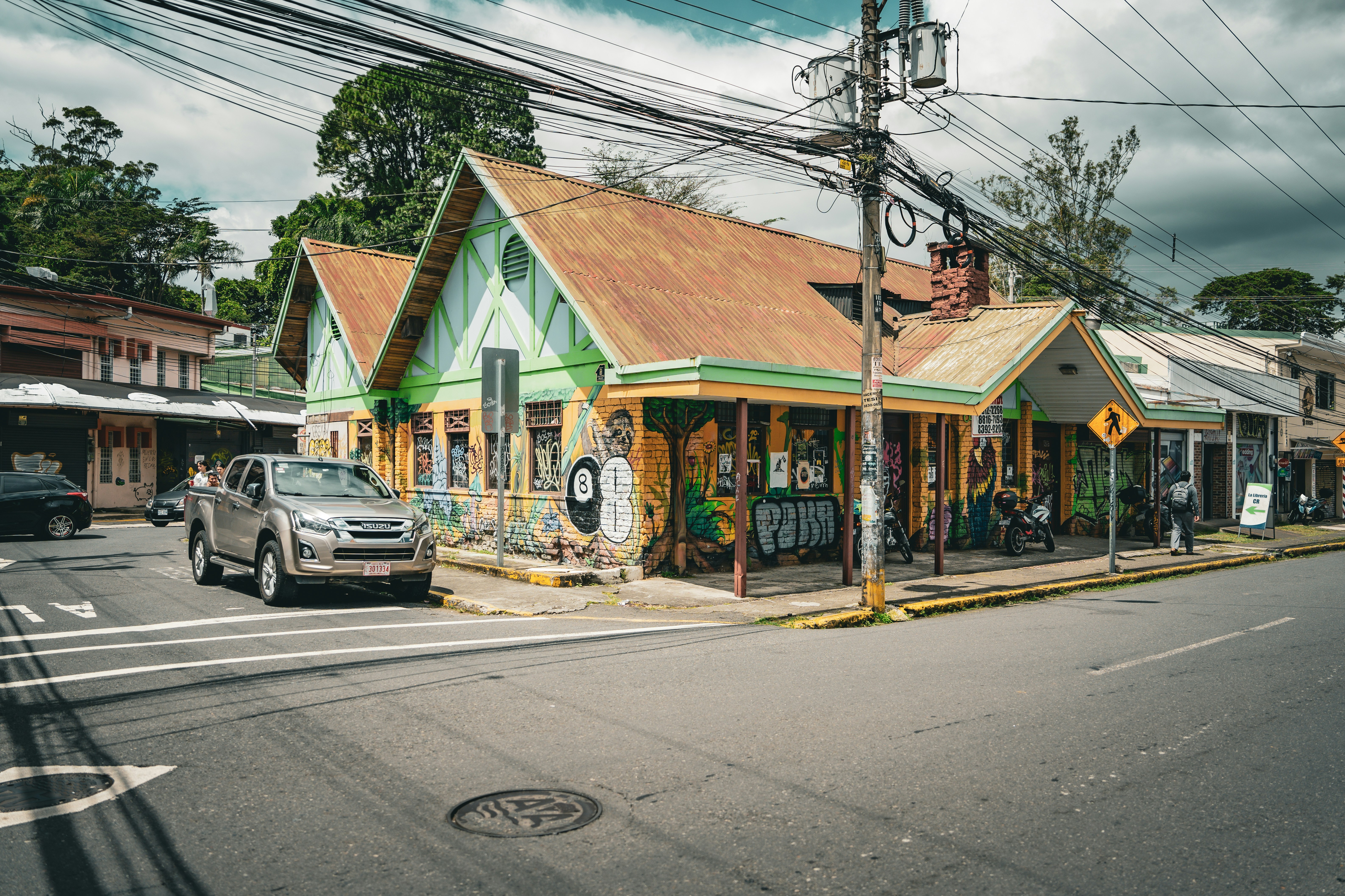 Par de una sesión de street photography en San Pedro, San José, Costa Rica | A street scene with colorful buildings and a car.