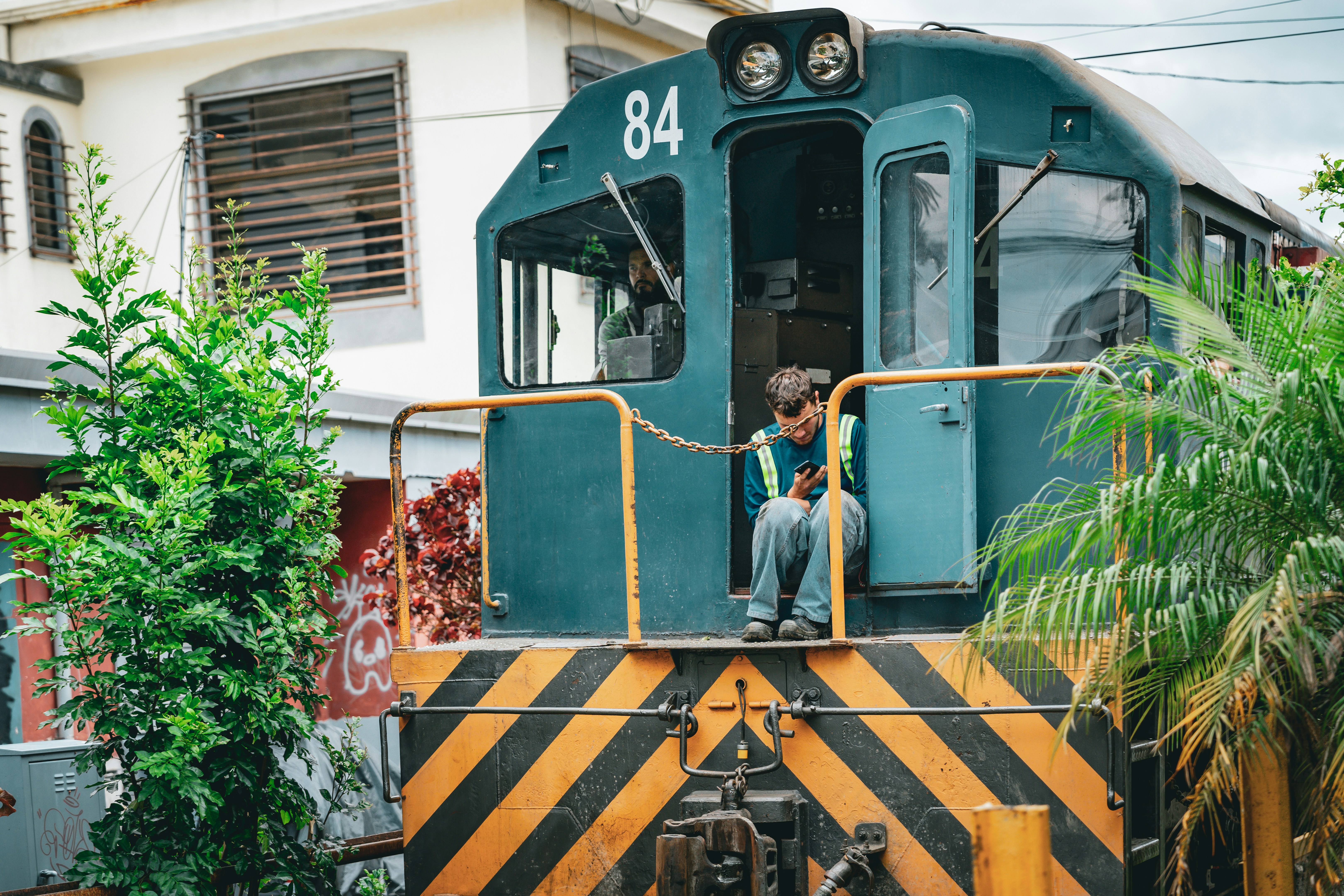 Par de una sesión de street photography en San Pedro, San José, Costa Rica | A person sits on the front of a teal train.