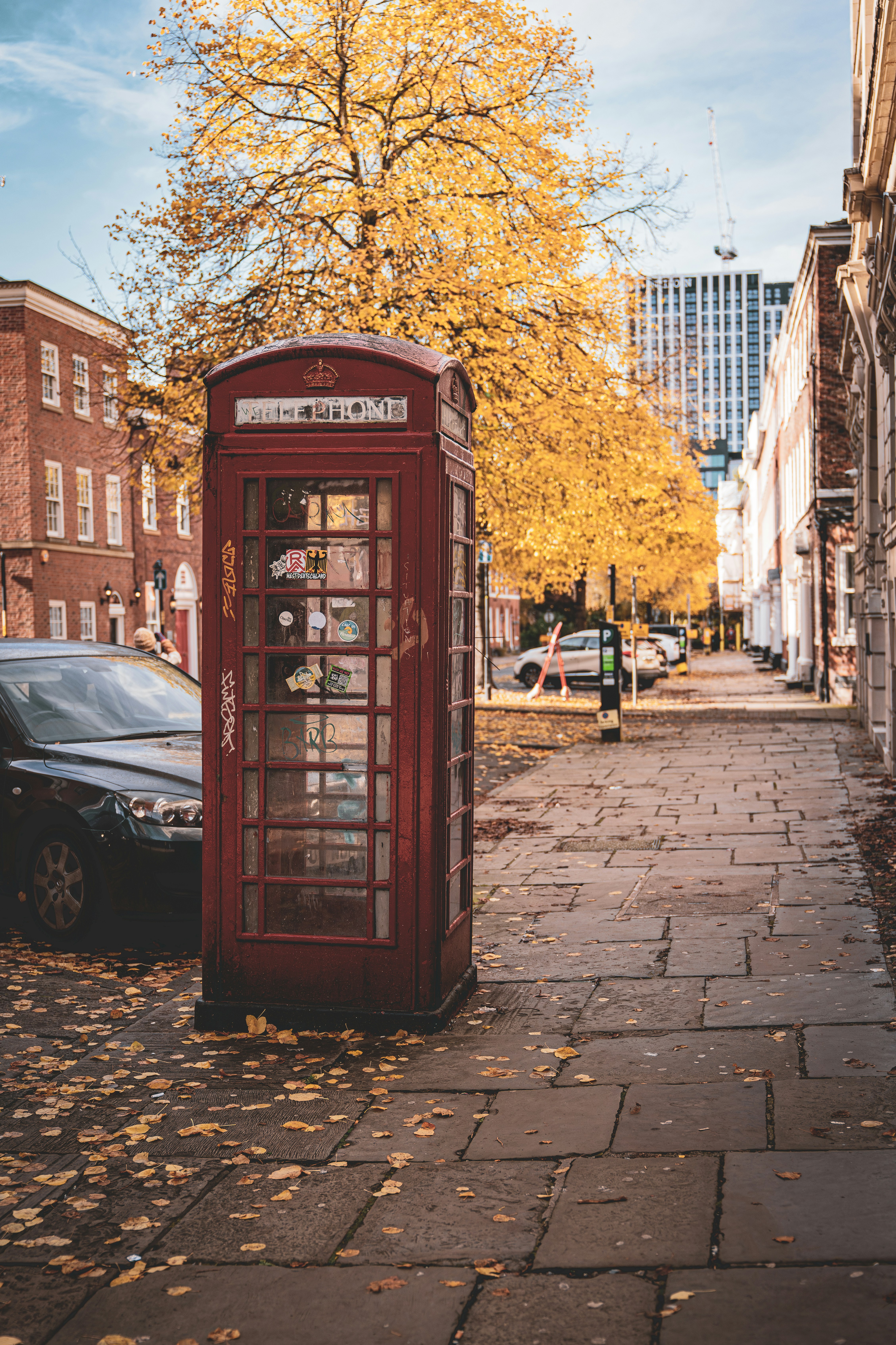 Red telephone box on a street with autumn leaves photo – Free Building ...