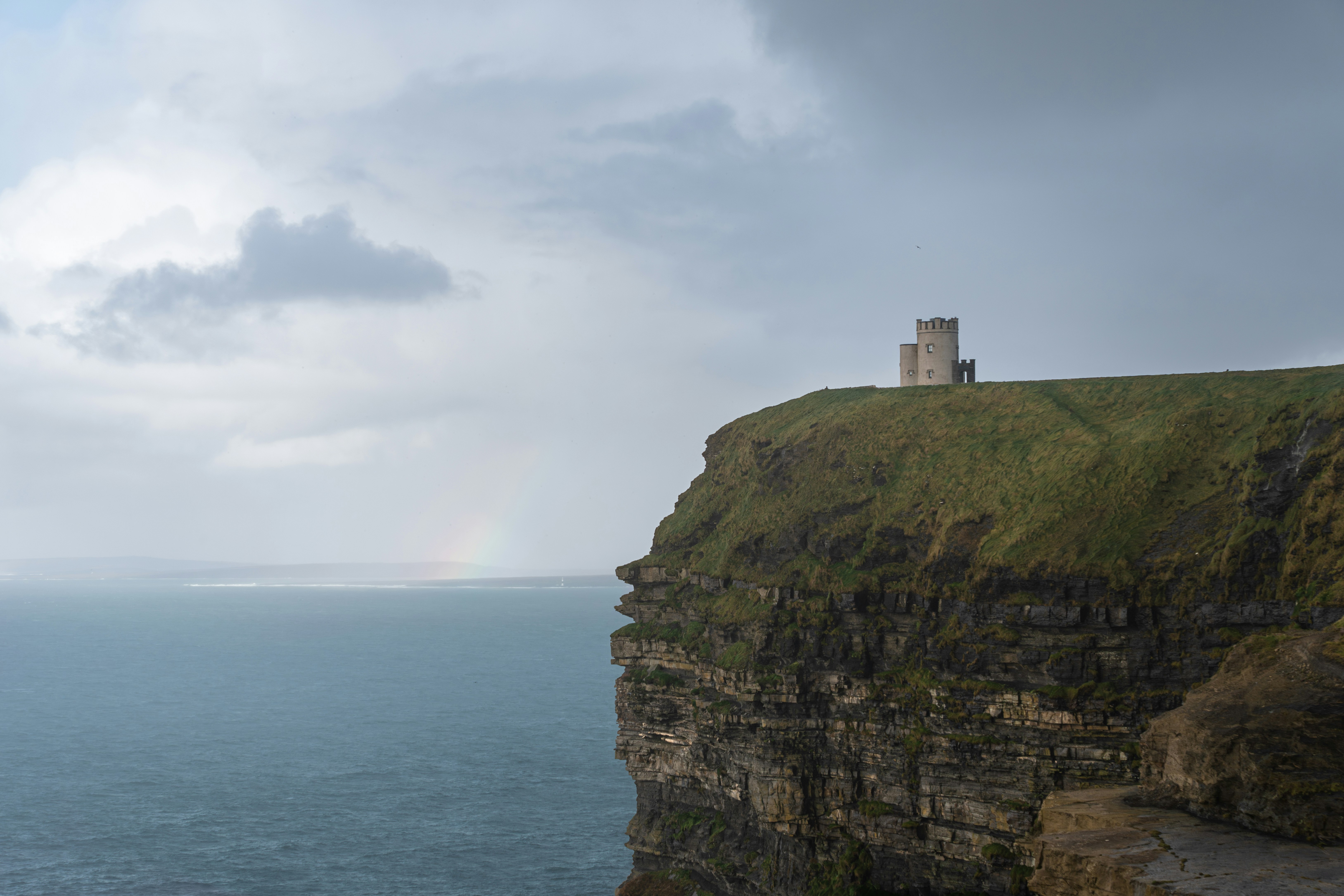 Cliffside tower overlooking the ocean under cloudy sky