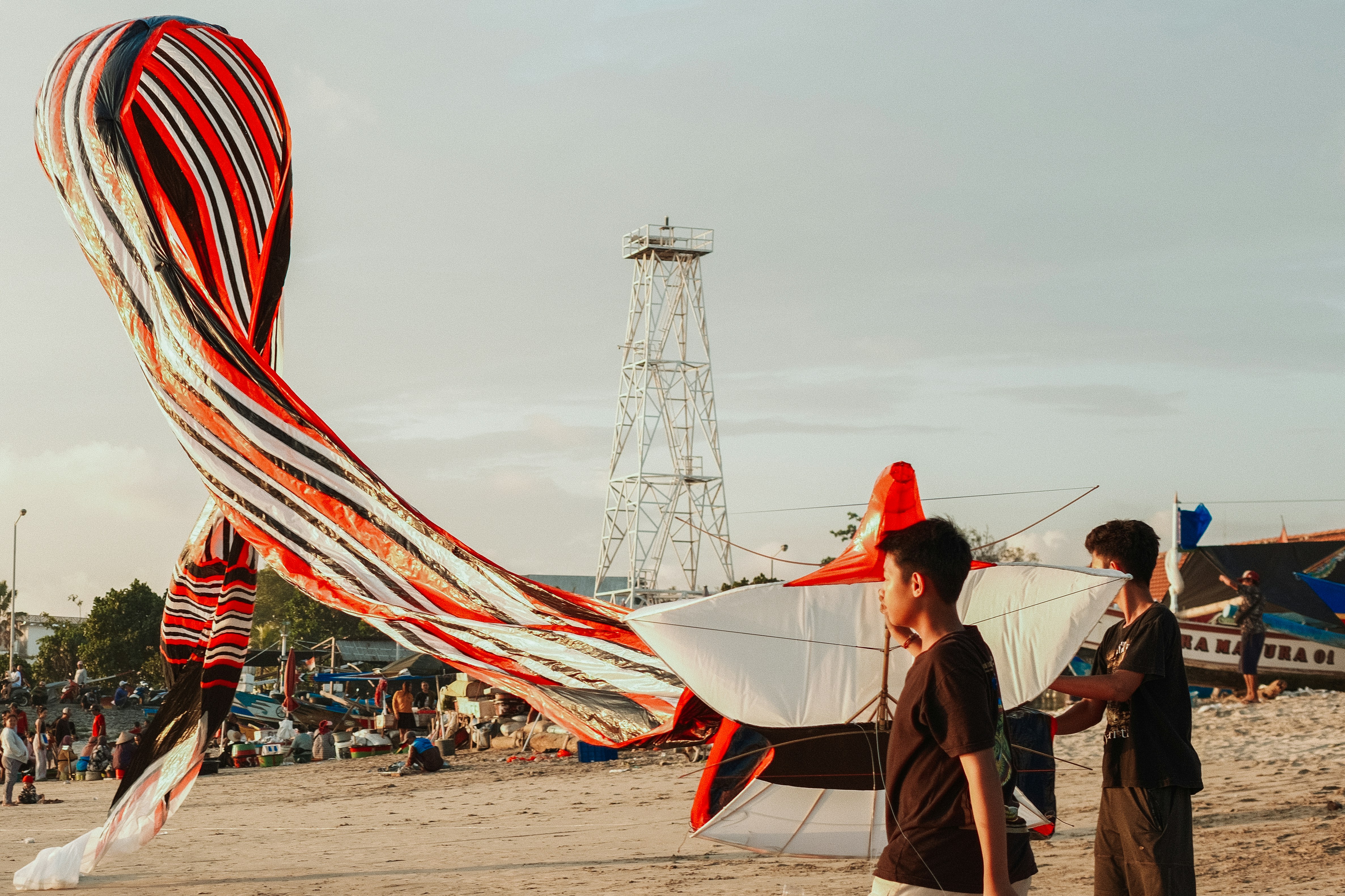 Unfurling Giants: A Red-White Kite Anchors a Beach Scene