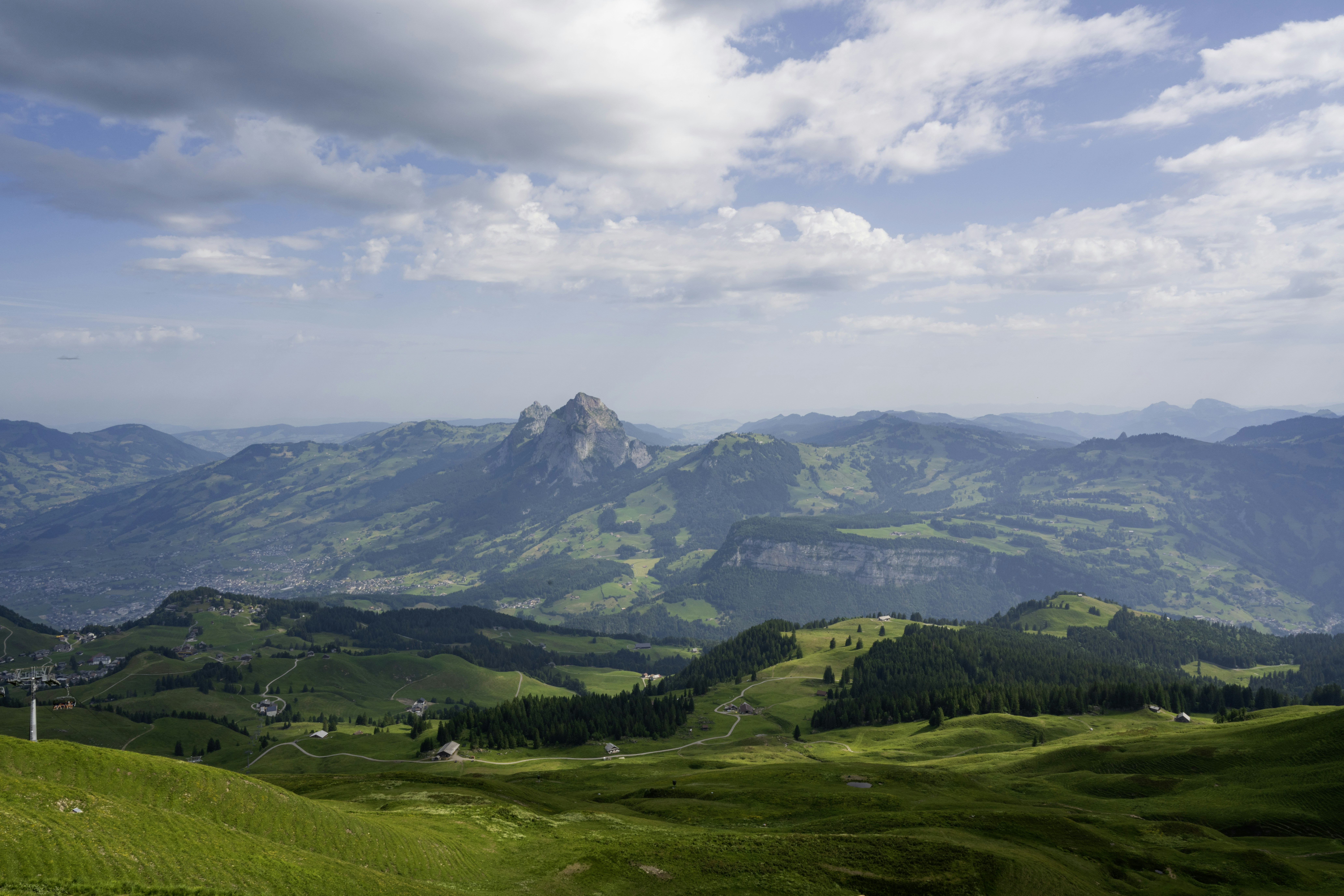 Rolling green hills and mountains under a cloudy sky.