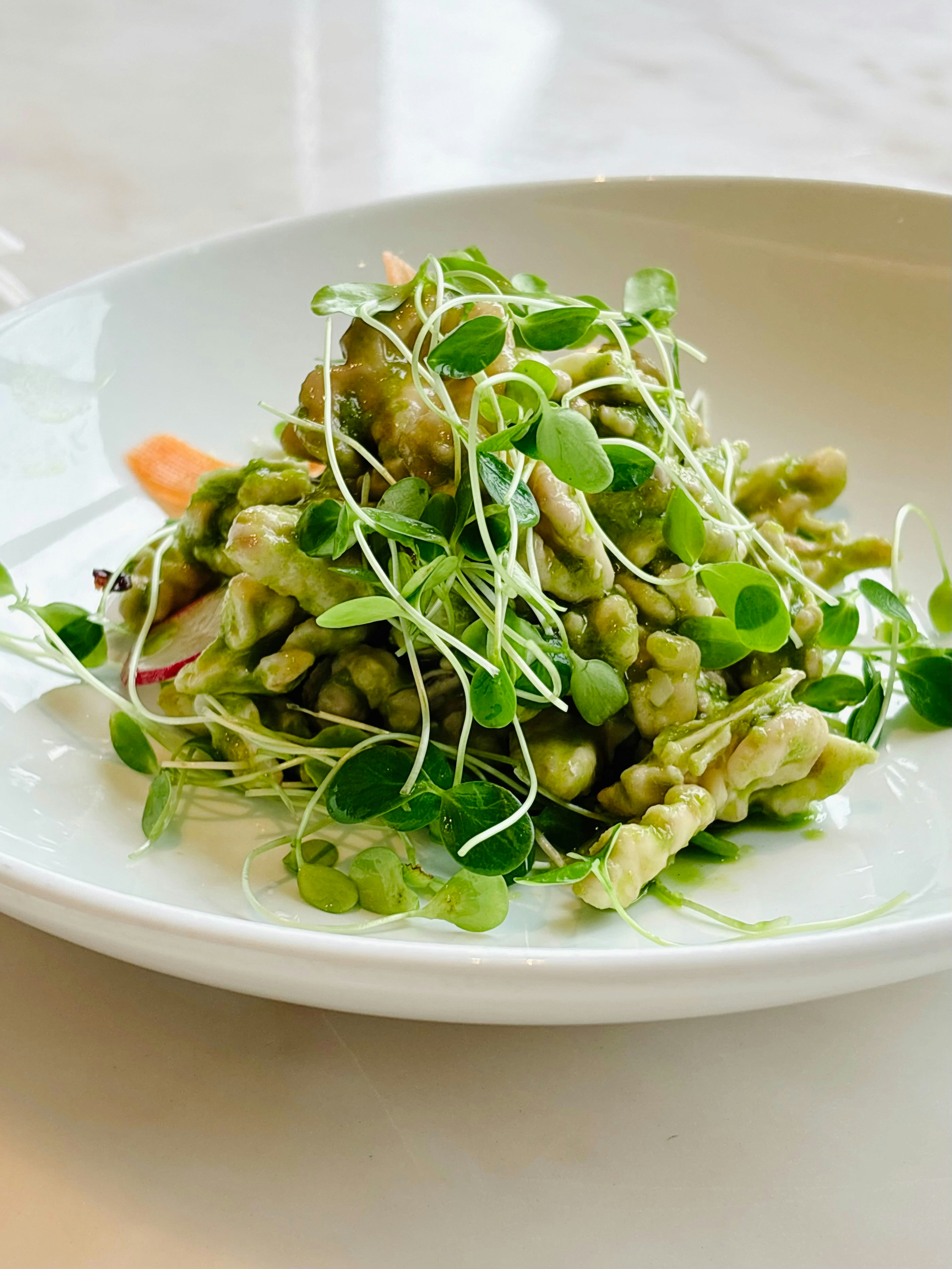 Green pasta dish with fresh sprouts and radish