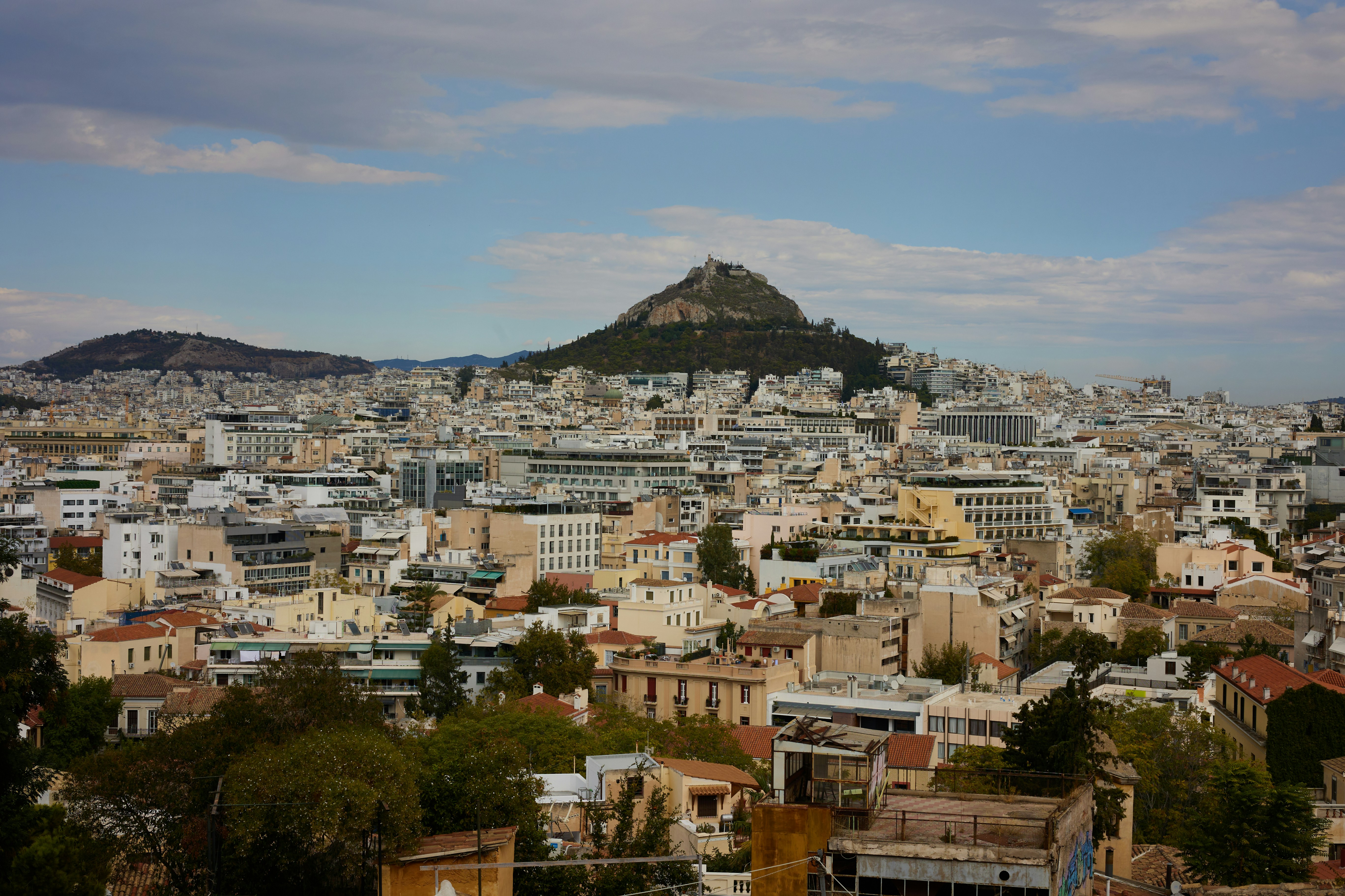 Cityscape with a prominent hill in the background.