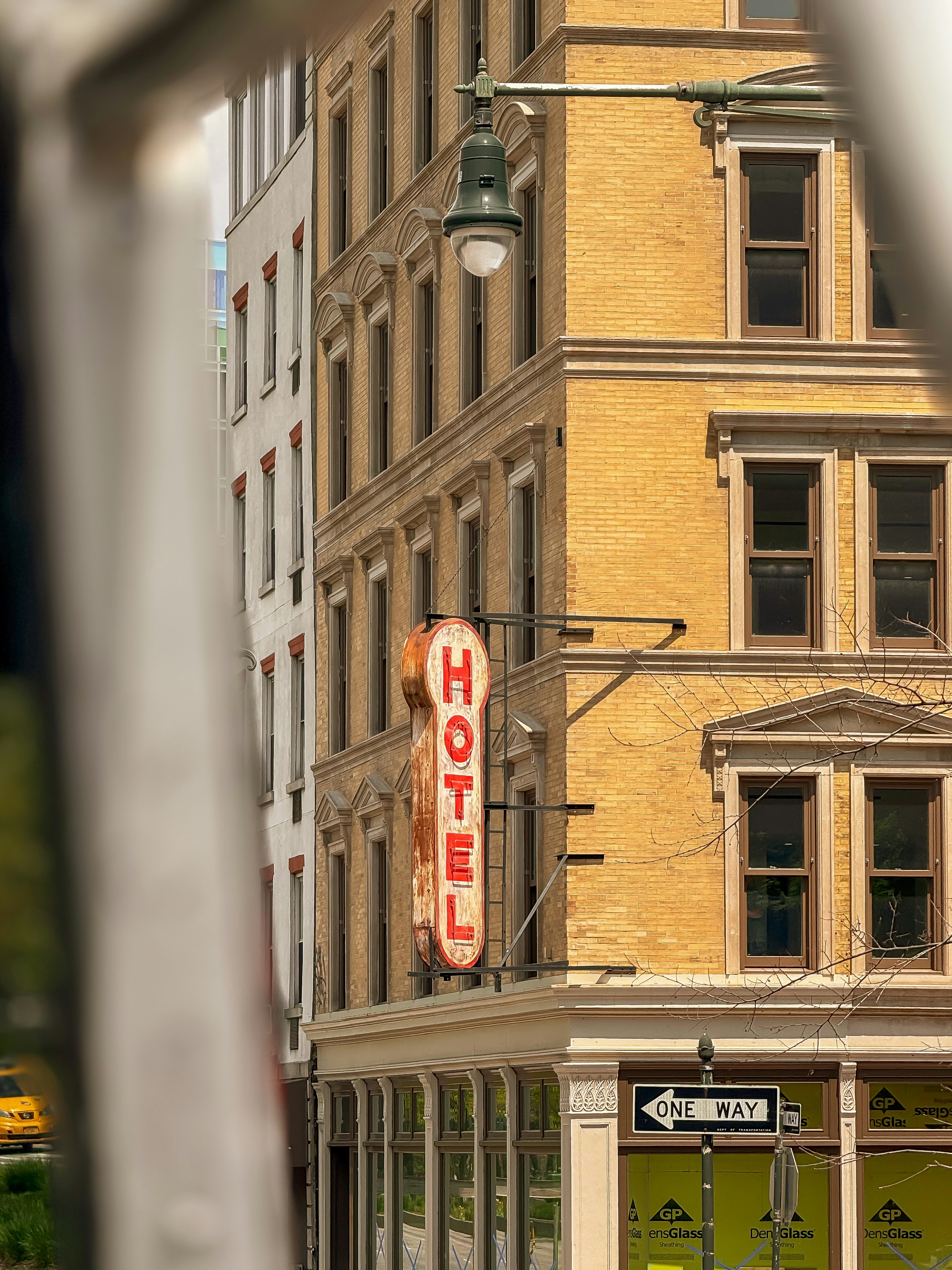Yellow hotel building with a neon sign.