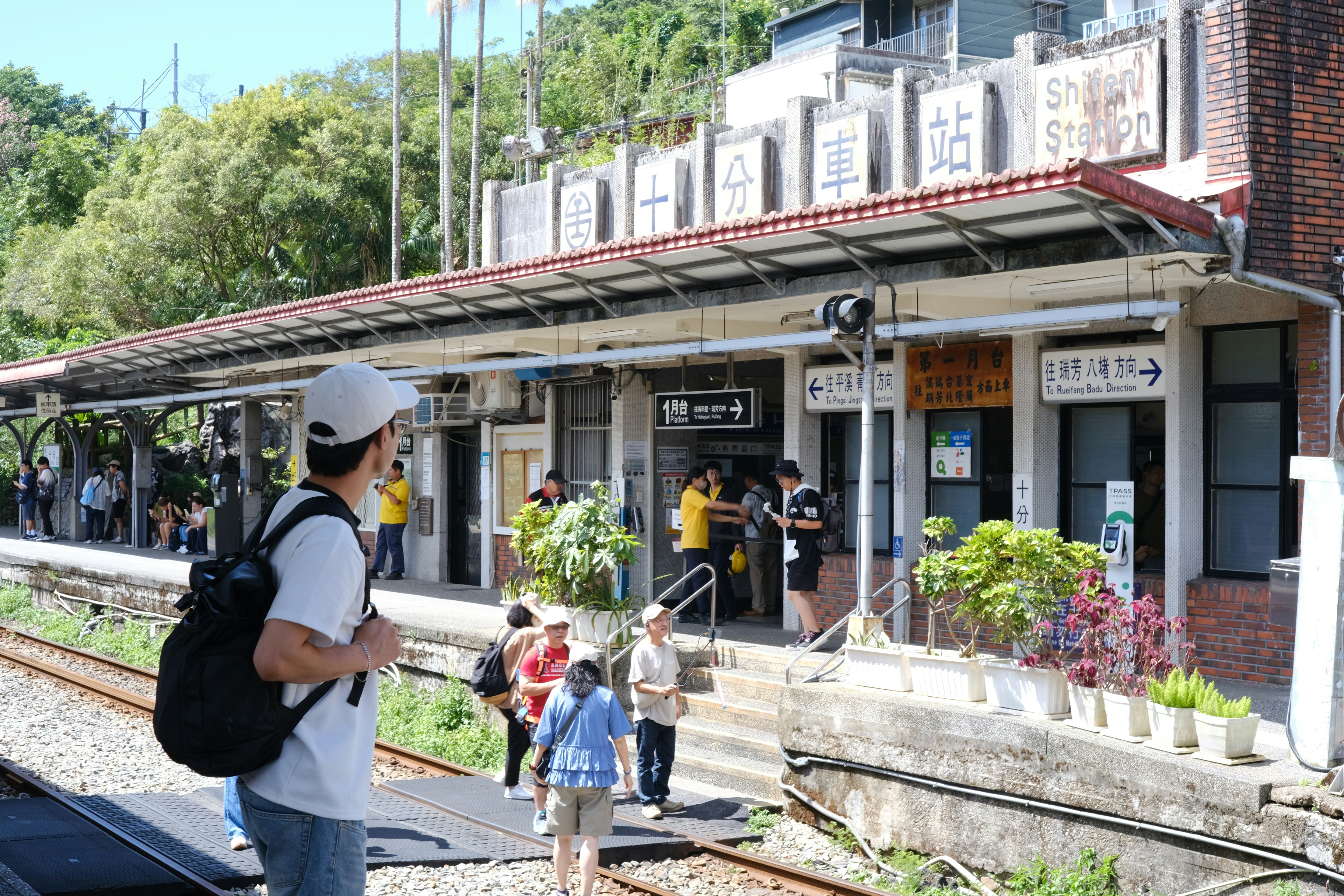 People at a train station platform on a sunny day
